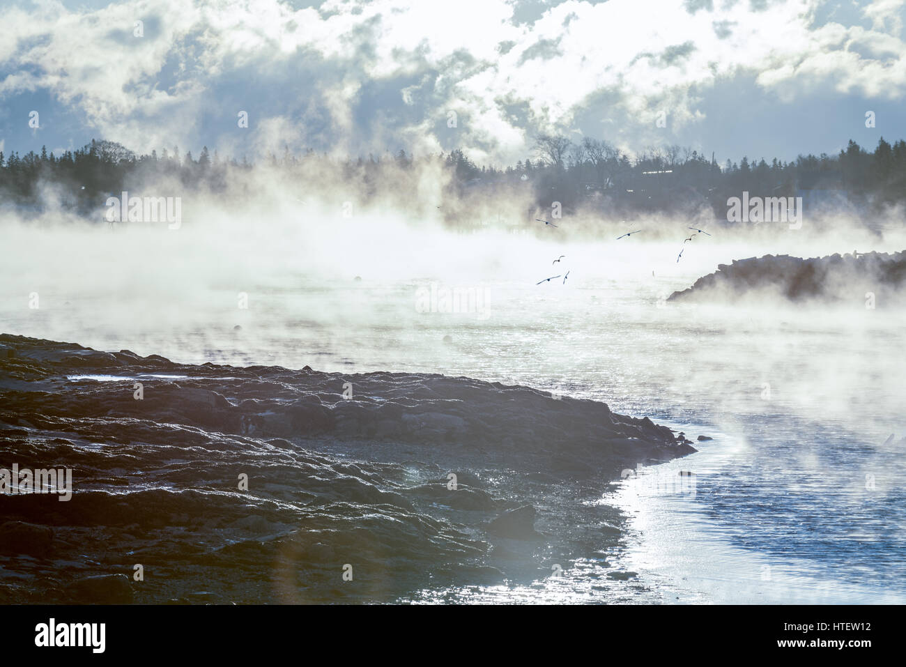 Sea smoke rises from the surface and surrounds lobster boats with ...