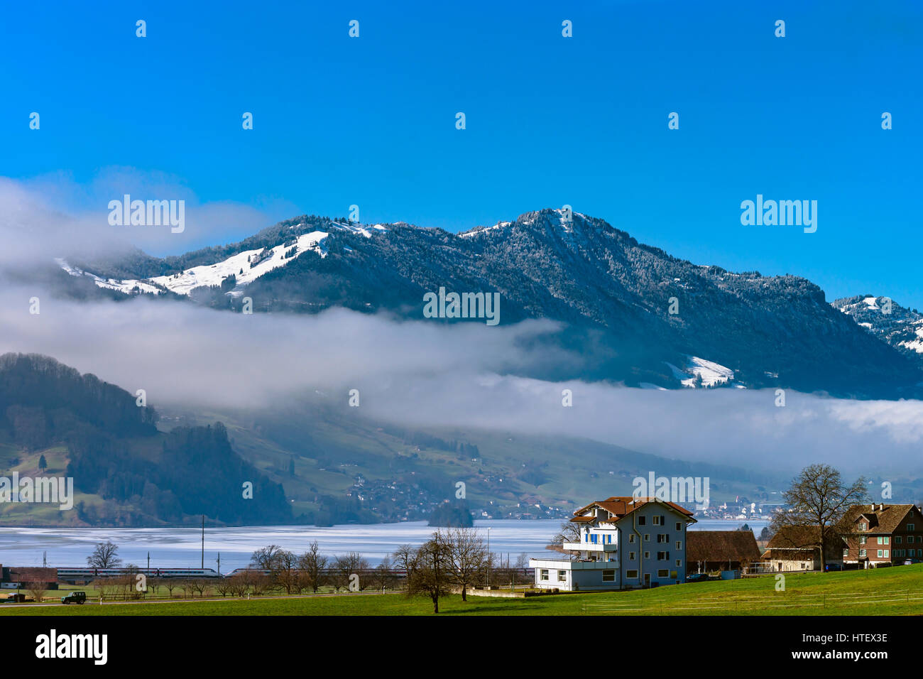 Alpine natural landscape with green fields, high rocks and white clouds ...