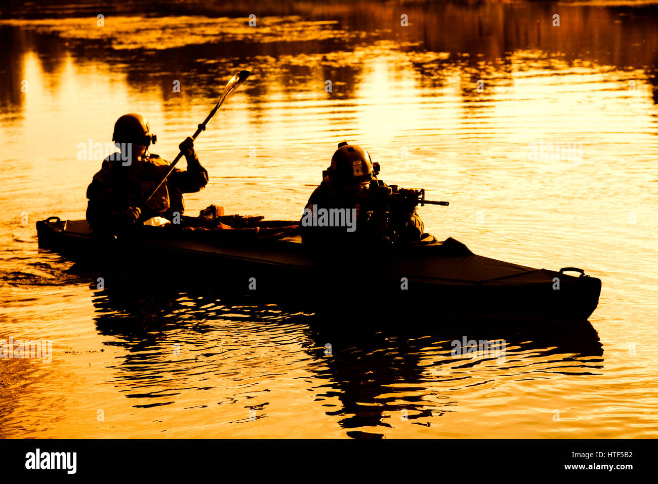 Silhouette of special forces men paddling army kayak. Boat moving ...
