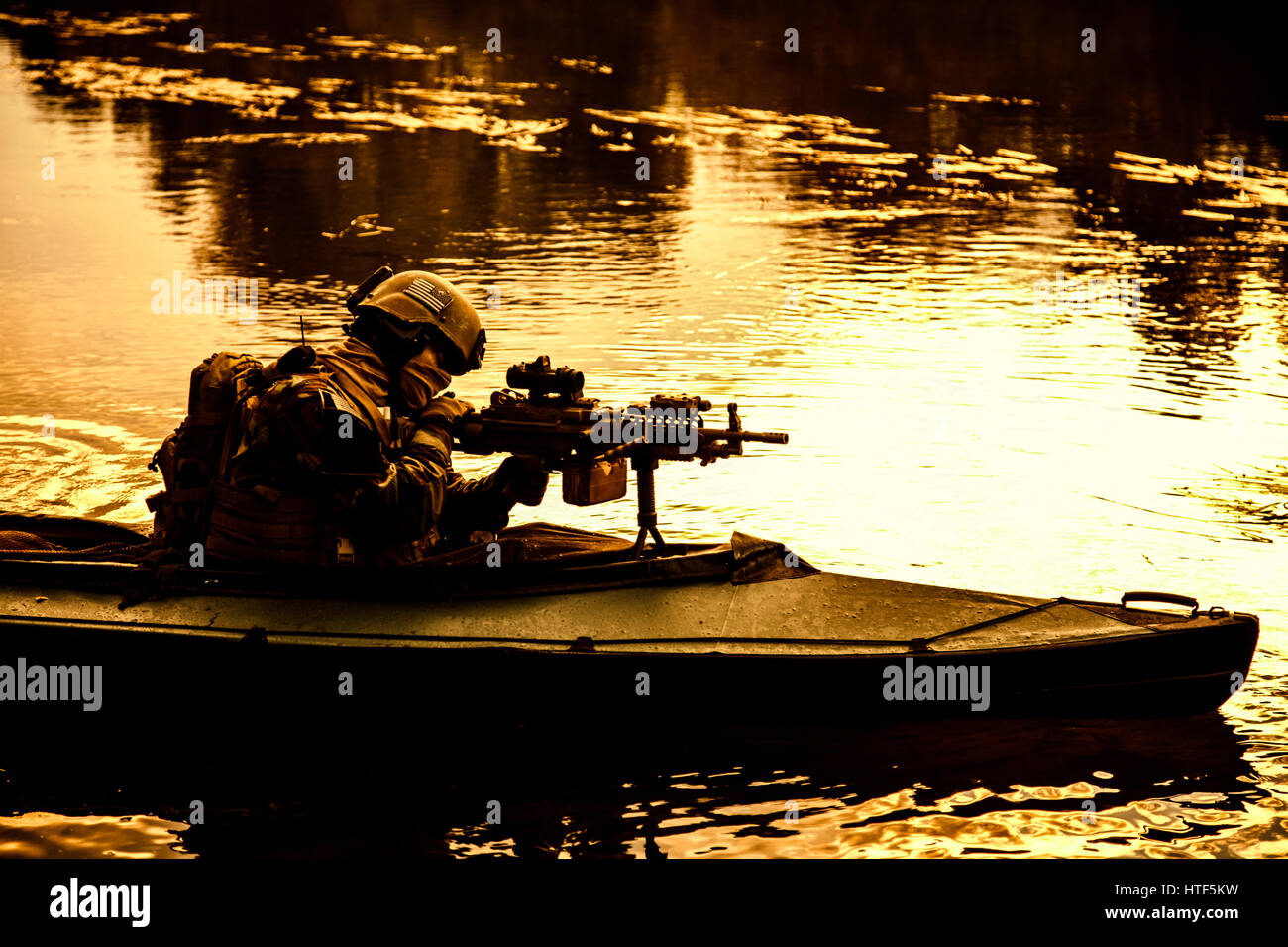Special forces backlit machine gunner in army kayak. Boat moving calmly ...