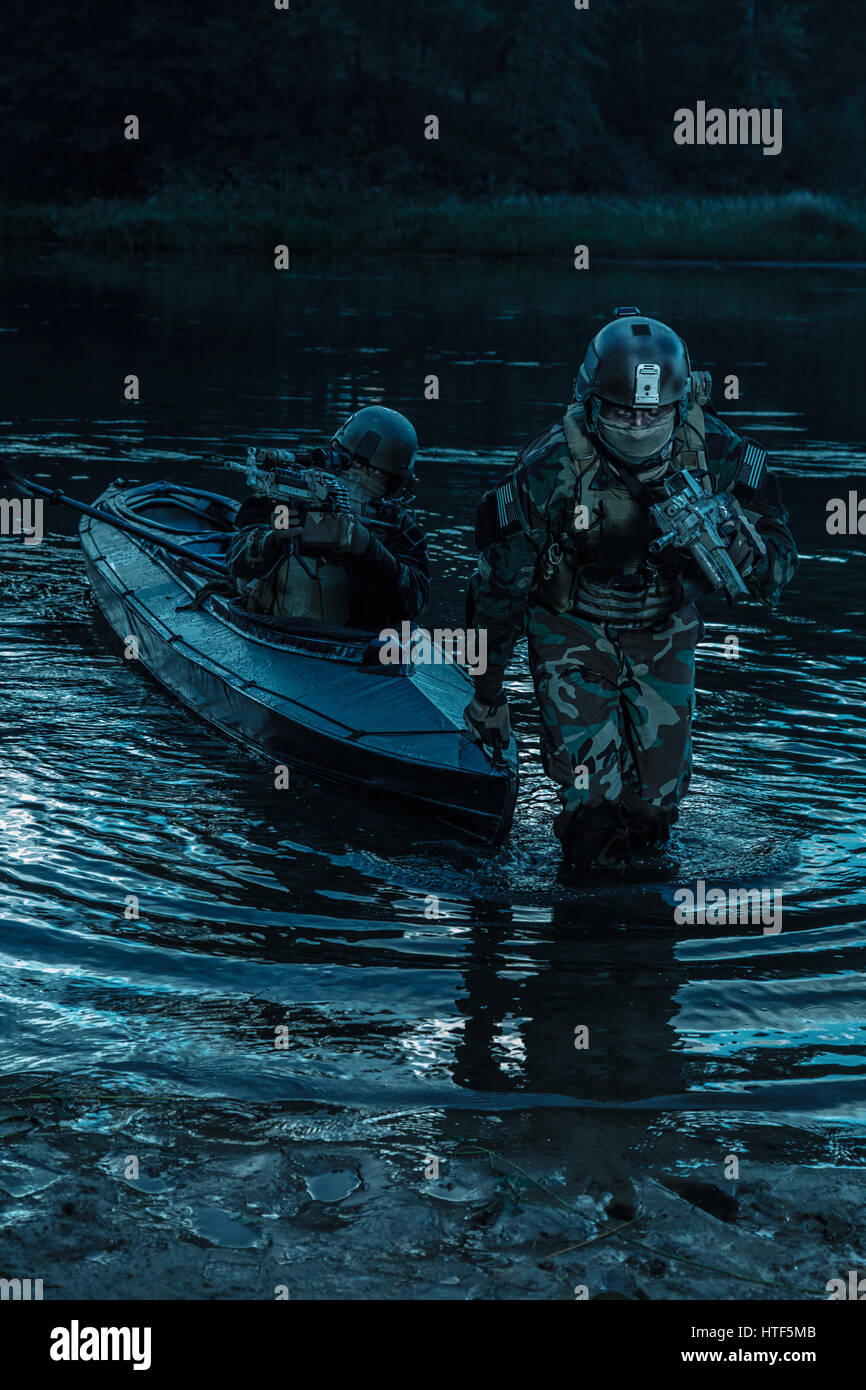 Covert landing. Pair of armed operators with painted faces disembarking ...