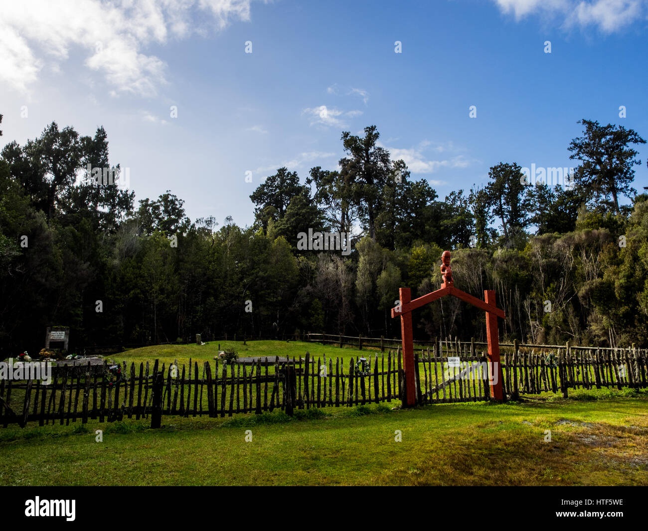 Carved figure of ancestor Tutoko over gateway in totara stake fence ...