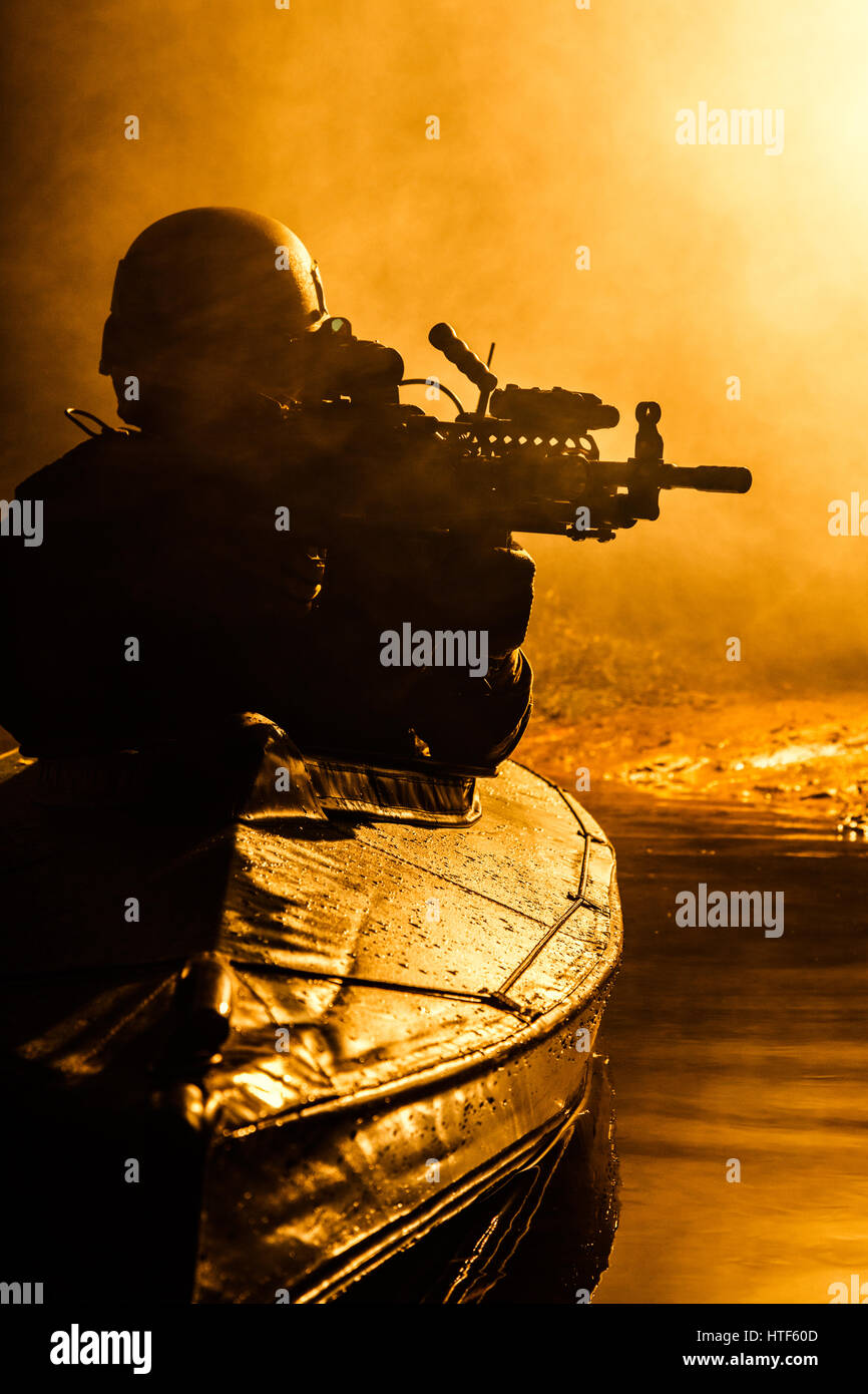 Backlit silhouette of special forces marine operators in military kayak ...