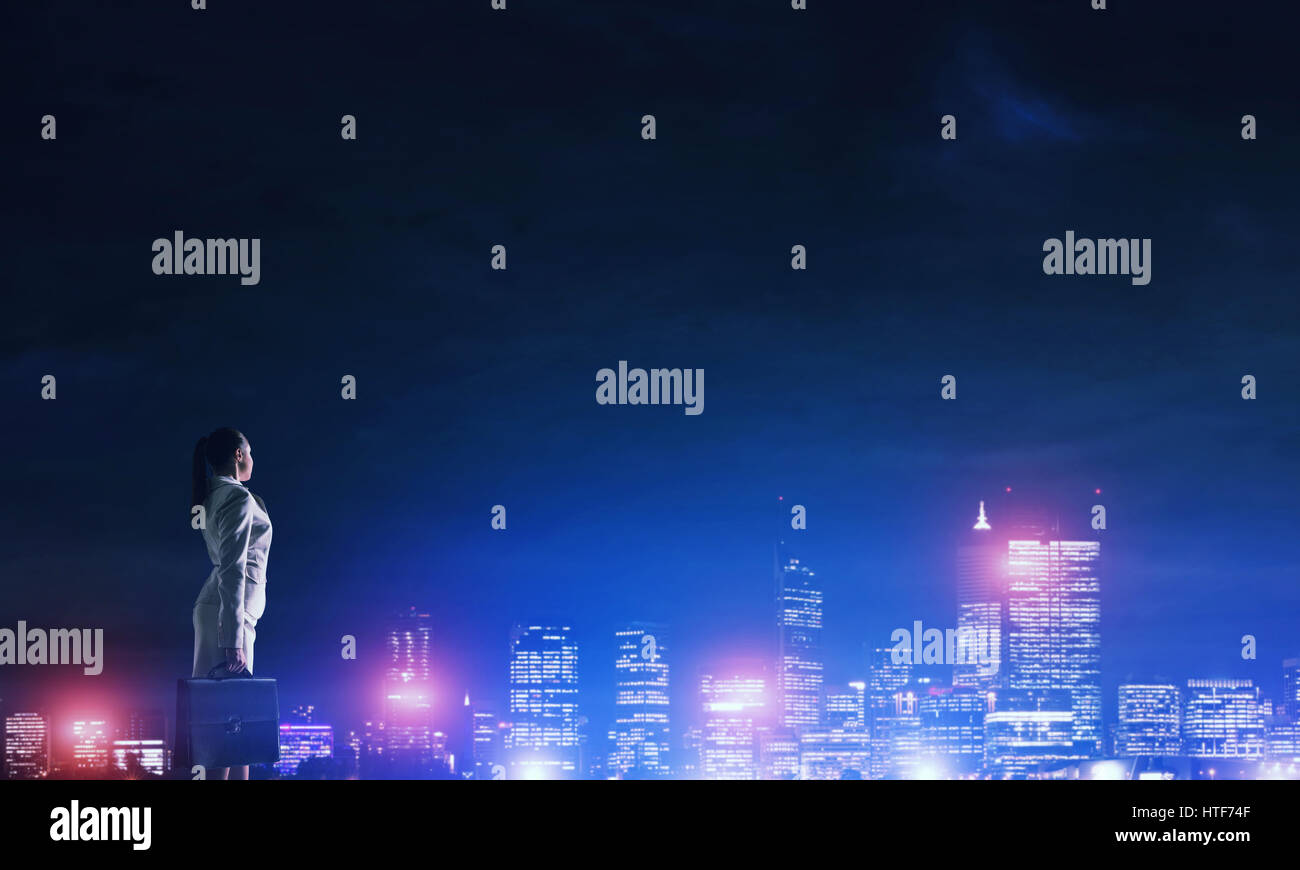 Rear view of elegant businesswoman viewing lights of night city Stock ...