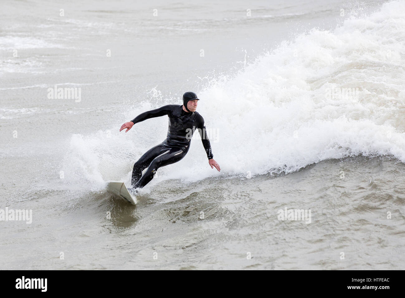A surfer takes advantage of stormy seas at Bournemouth, Dorset, England ...
