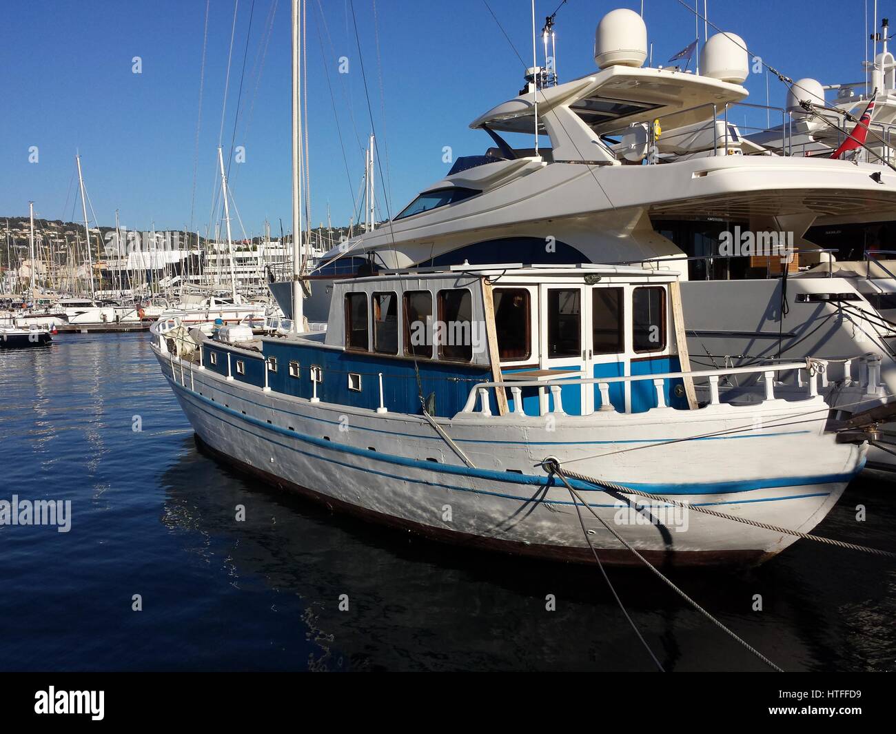 Old Mediterranean Caique boat docked alongside modern luxurious motor ...