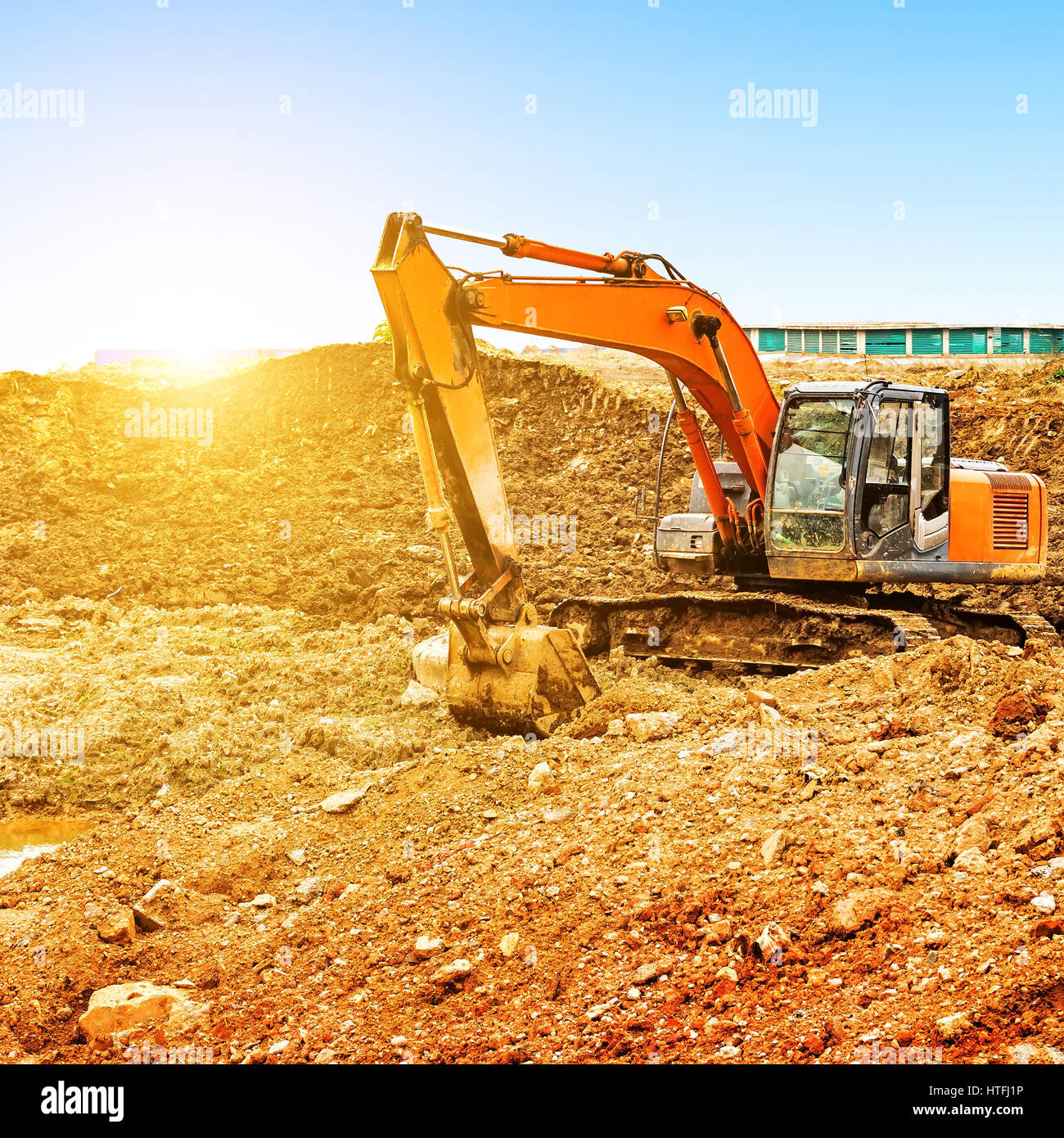 Excavator under blue sky background Stock Photo - Alamy