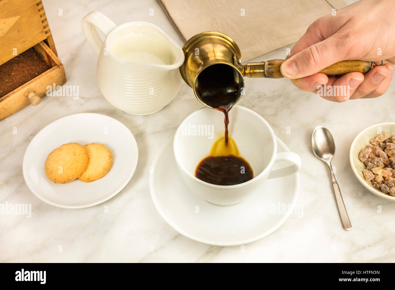 Coffee poured into a cup from a coffee pot, with a milk jar and cane ...