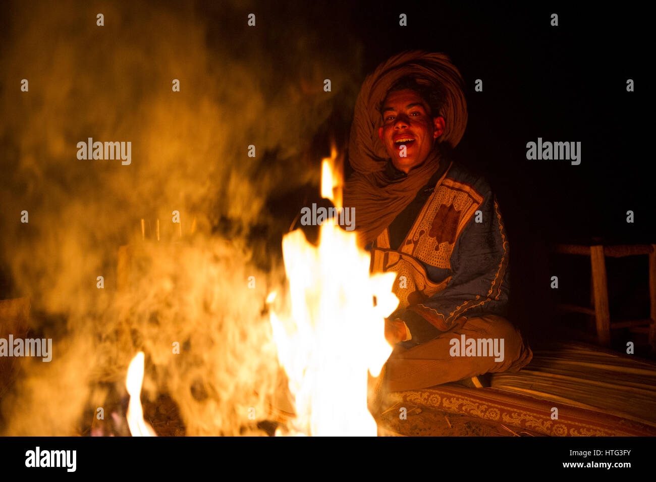 A nomadic Berber man singing next to a camp fire in the Sahara Desert ...