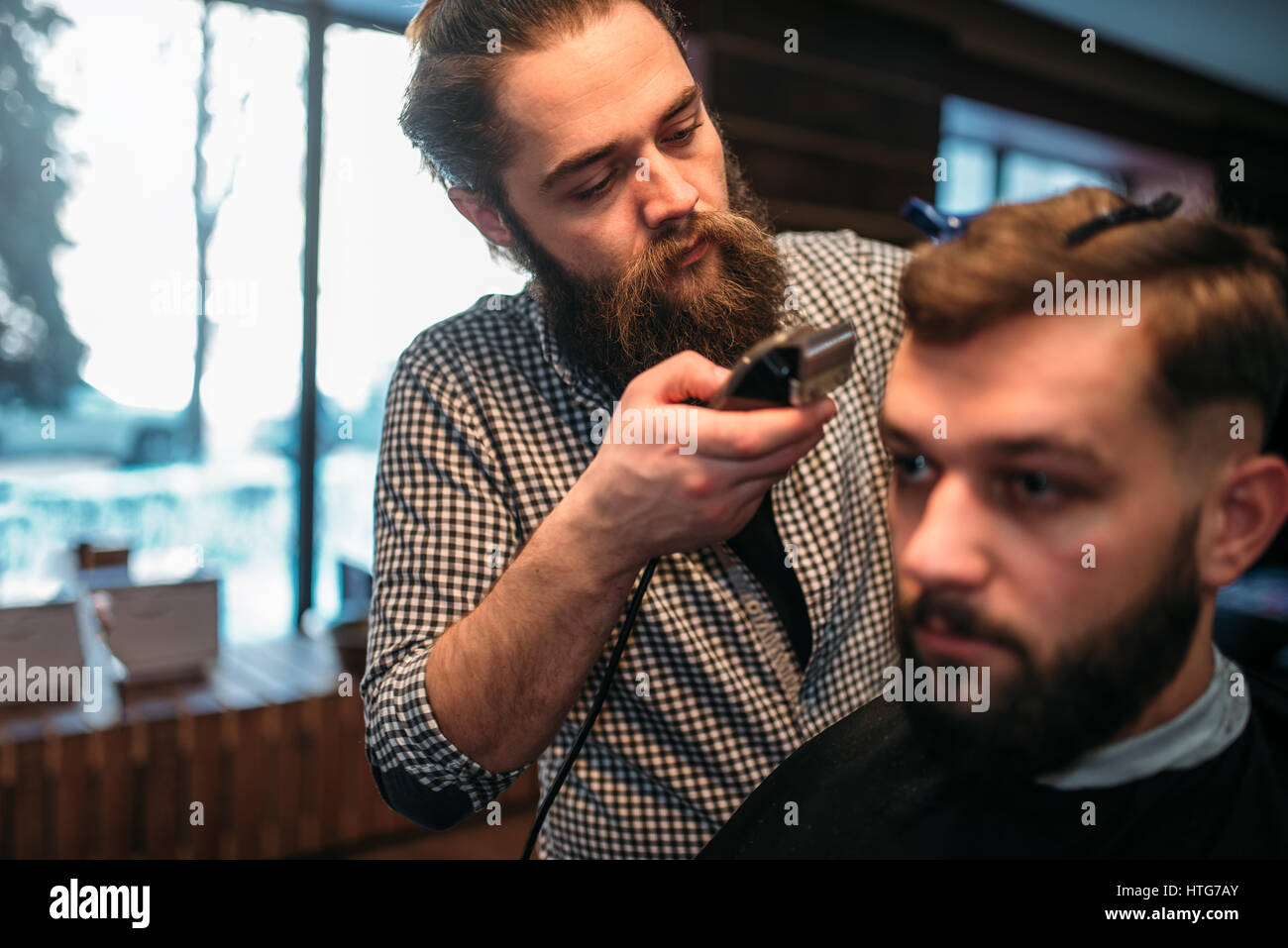 Barber working by clipper with hairstyle of the client man in black ...
