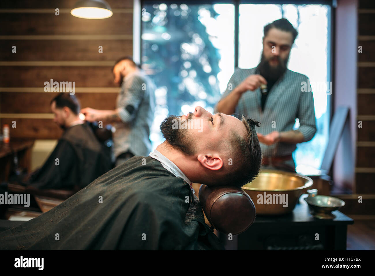 Bearded man in salon cape at the barbershop, barber on background Stock ...
