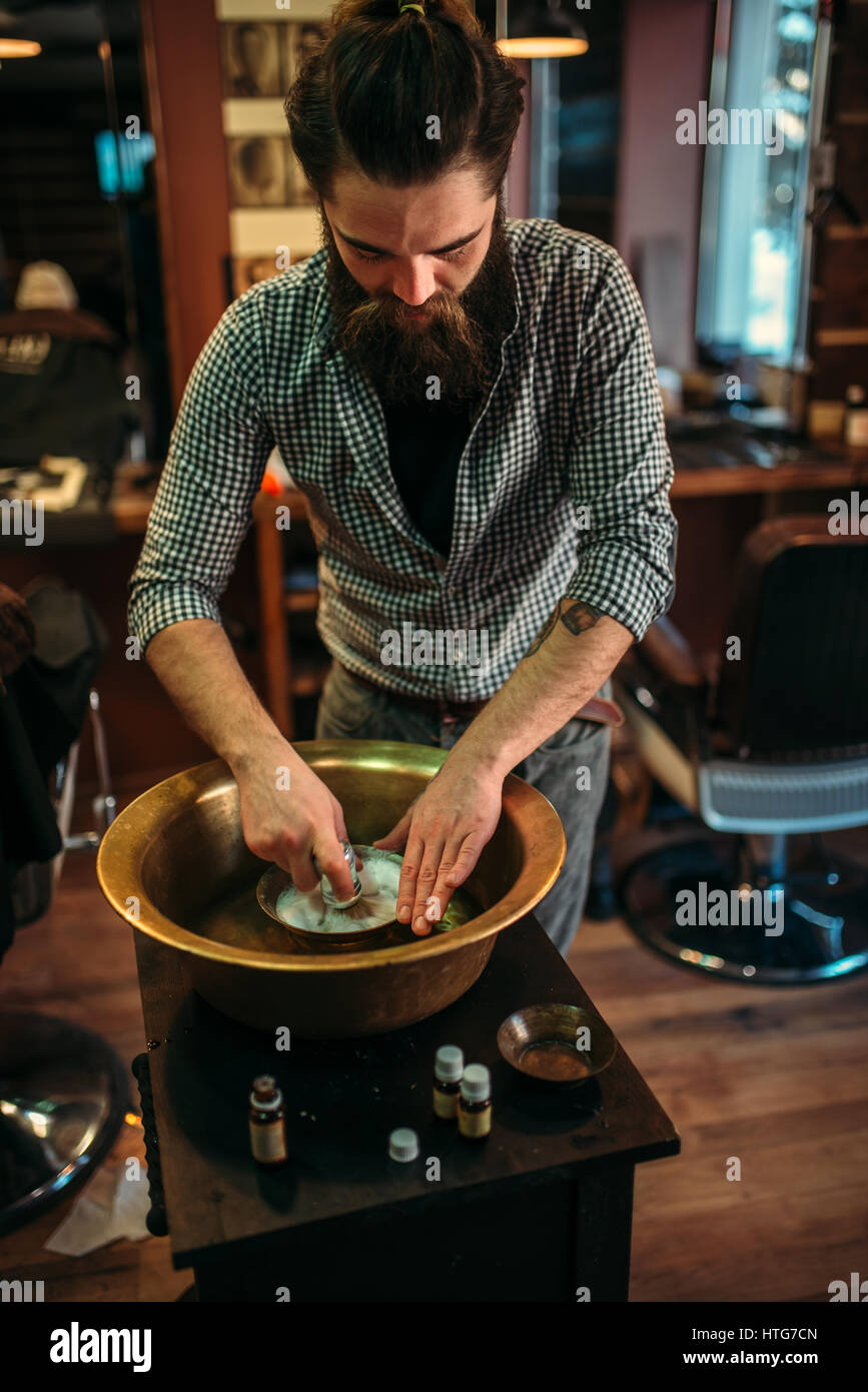 Barber preparing shaving foam in a copper bowl at barbershop ...