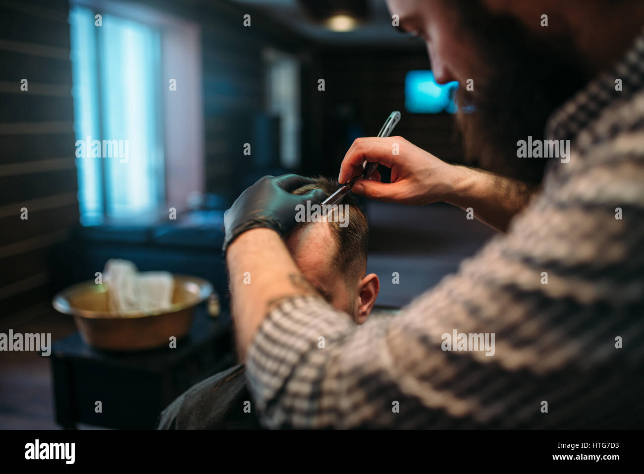 Barber shaves the hair with straight razor. Client man at barbershop ...