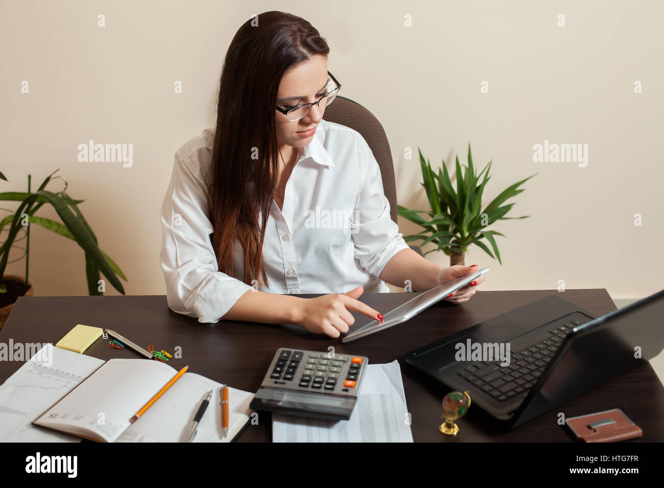 Female bookkeeper hands holding tablet pc. Table with laptop on ...