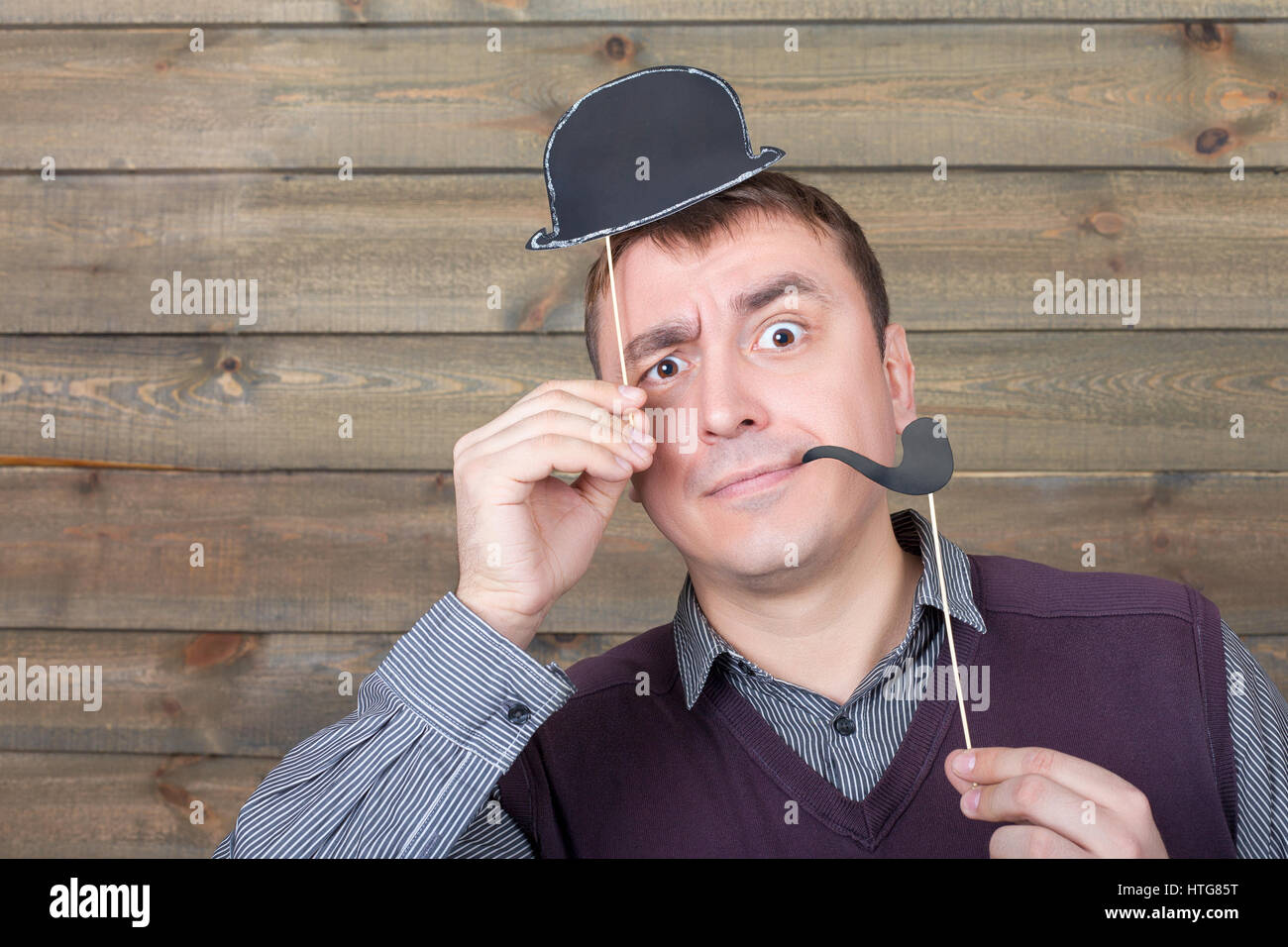 Young male with funny hat and smoking pipe on a sticks in hand, wooden ...