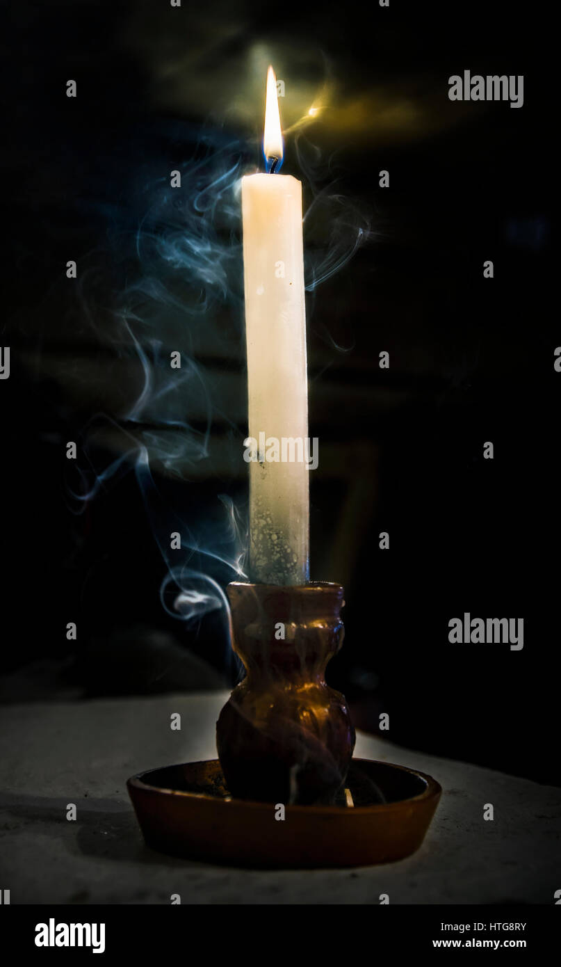 A burning candle with smoke in a clay candlestick Stock Photo - Alamy