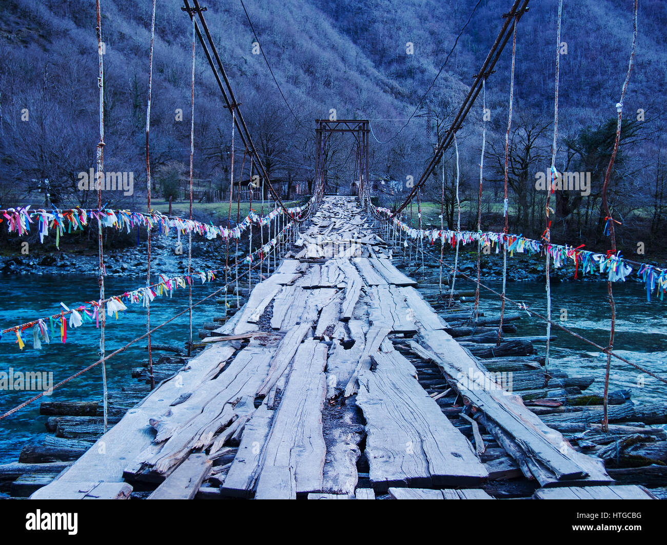 Old wooden bridge hanging over a gorge and mountain stream. Beautiful ...