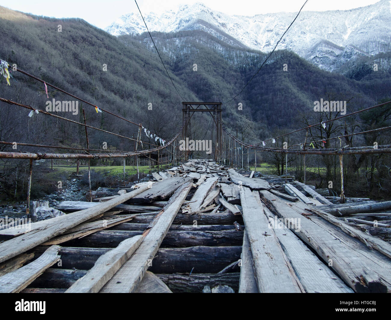 Old wooden bridge hanging over a gorge and mountain stream. Beautiful ...