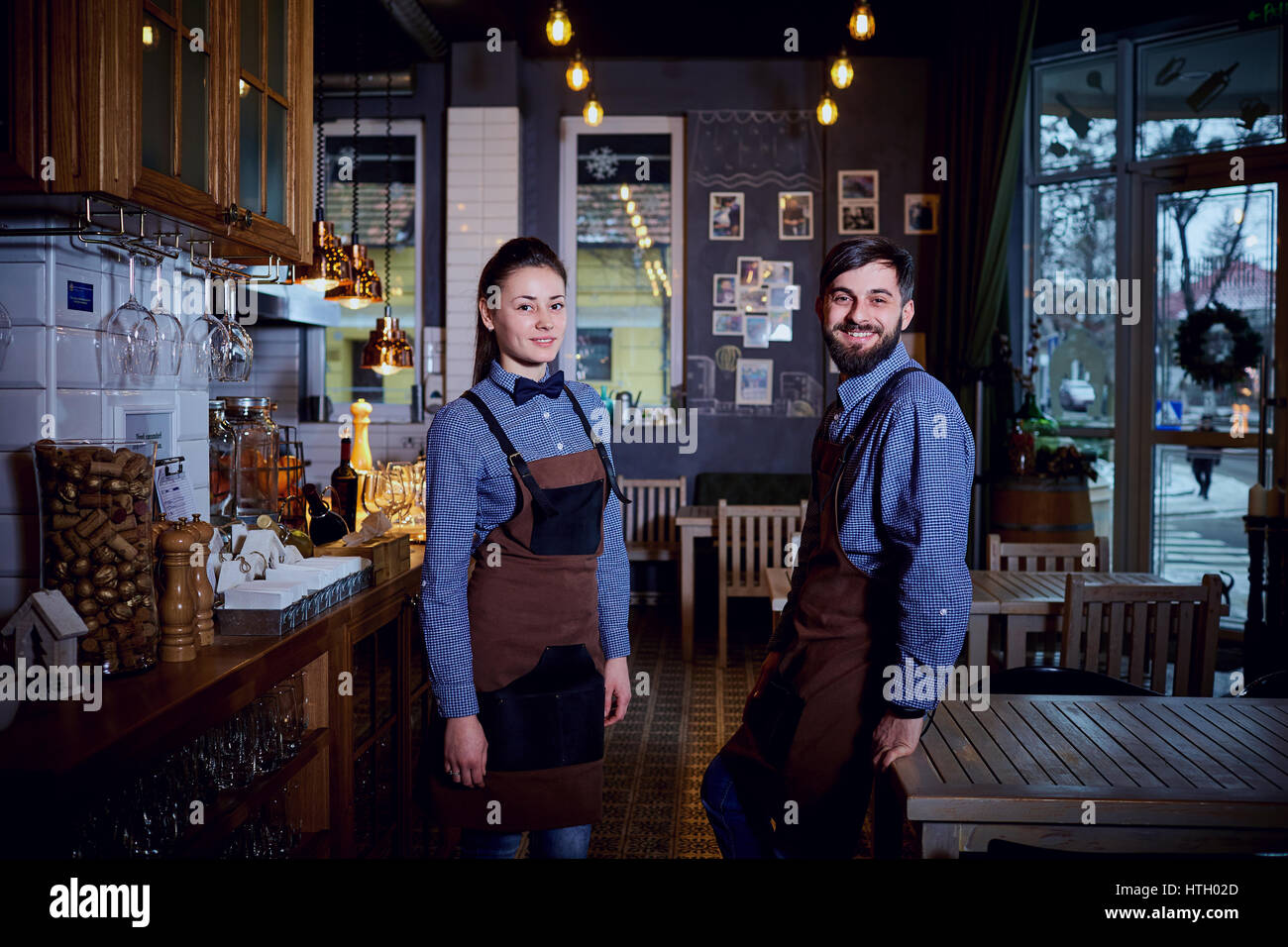 Two workers bartender barista girl and a man at work behind the bar in ...