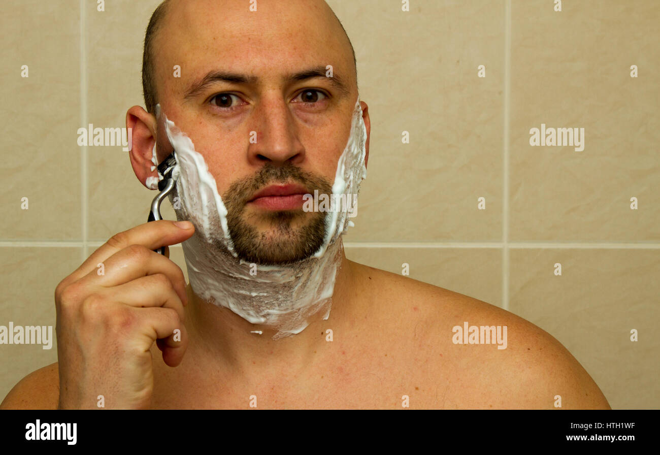 Man shaving his face with the razor blade through shave foam. Men skin ...