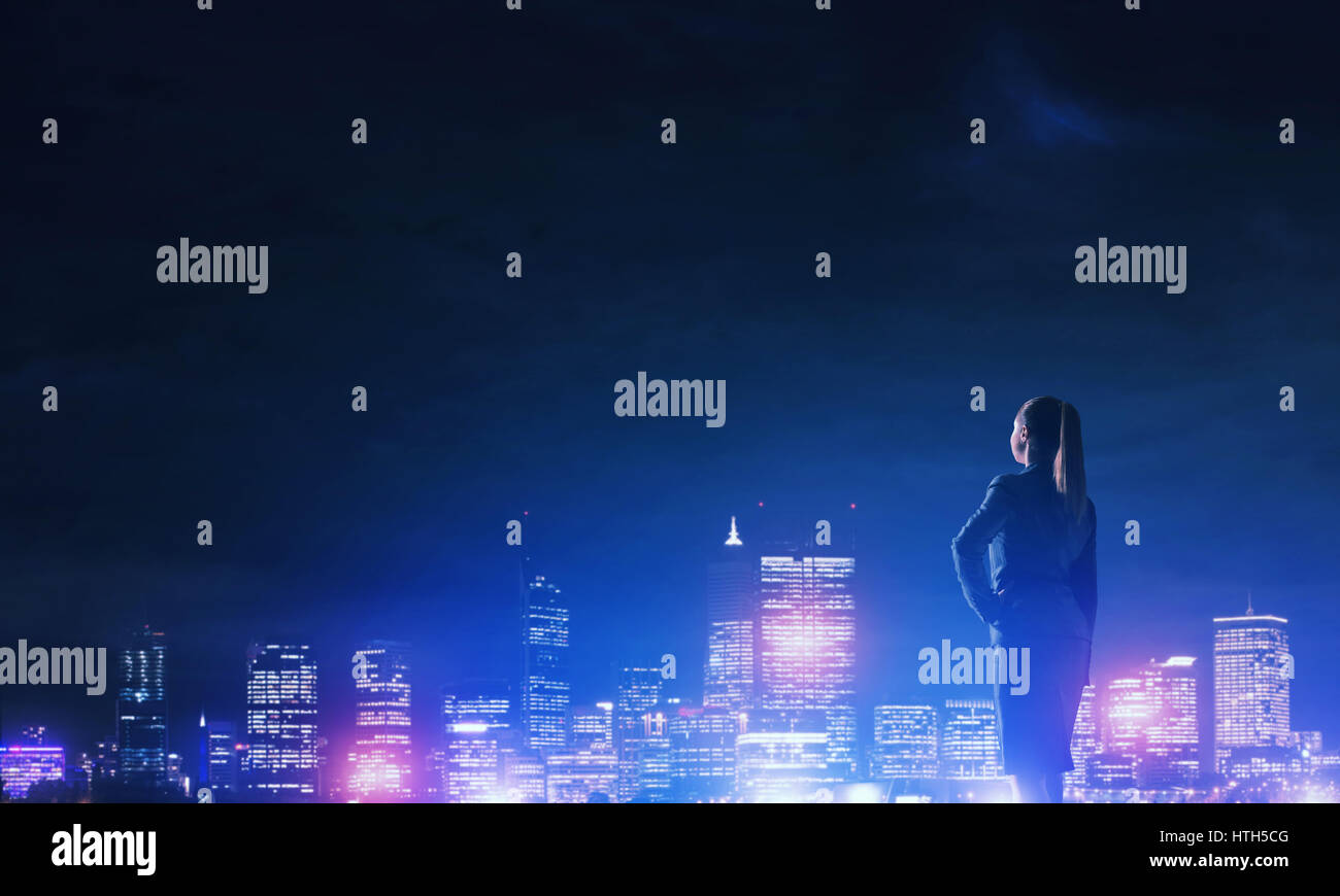 Rear view of elegant businesswoman viewing lights of night city Stock ...