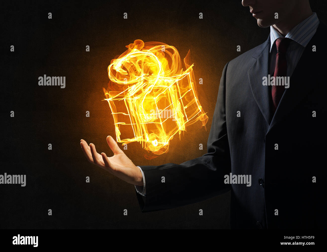 Glowing fire gift box icon in palm on dark background Stock Photo - Alamy