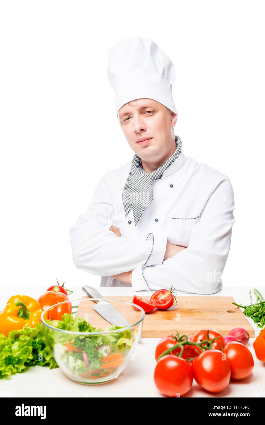 Vertical portrait of a cook at the table with vegetables on a white ...