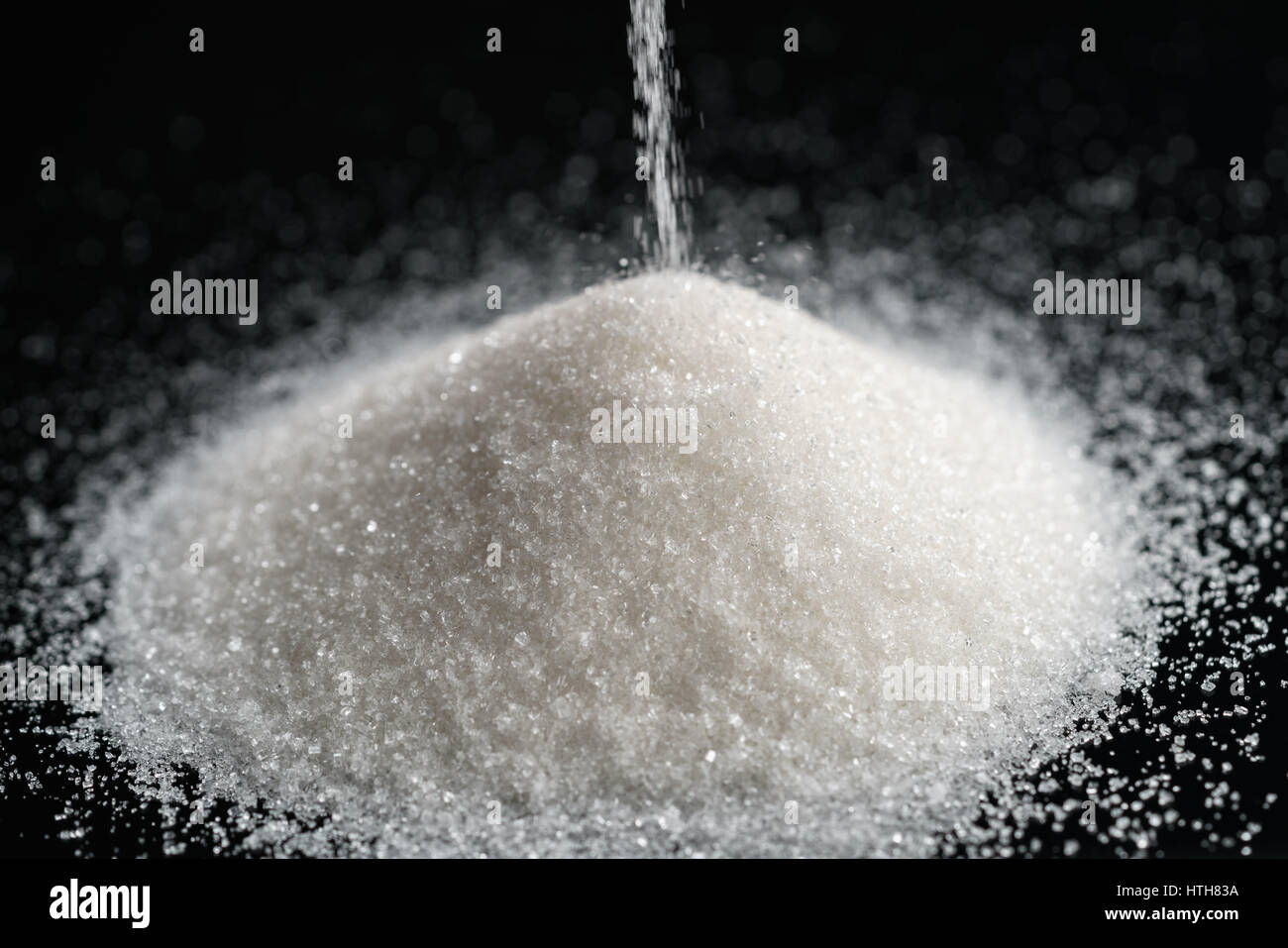sugar falling on black background, closeup photo Stock Photo - Alamy