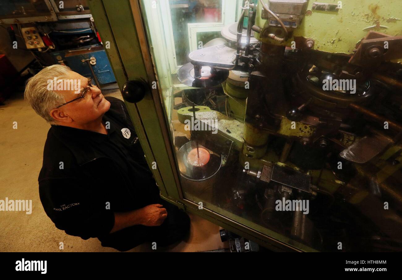 A pressing room operative observes seven inch records being pressed in ...
