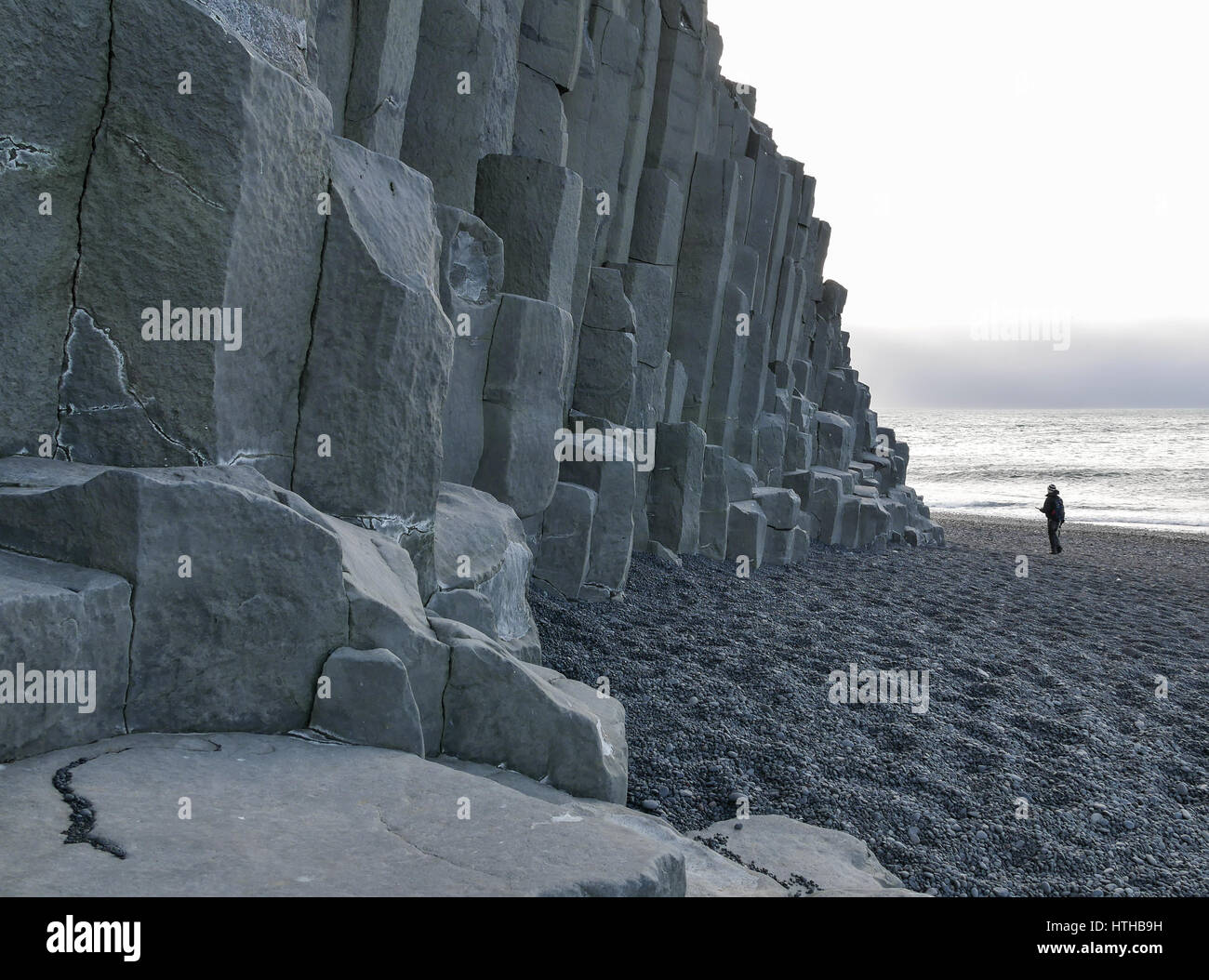 A solitary silhouette figure next to volcanic basalt hexagonal pattern ...