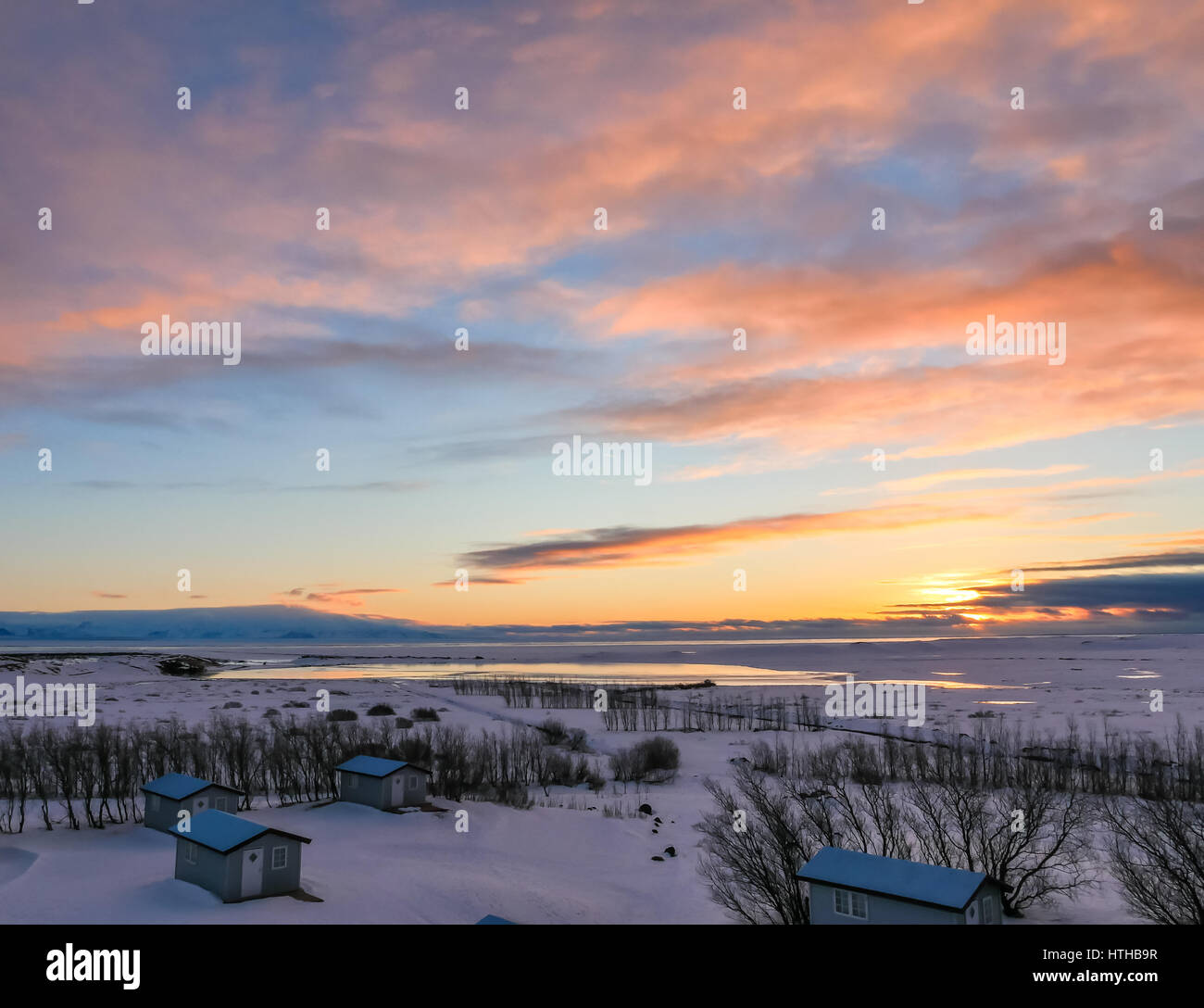 Colourful sunrise on a low horizon in winter in Iceland, with bungalow ...
