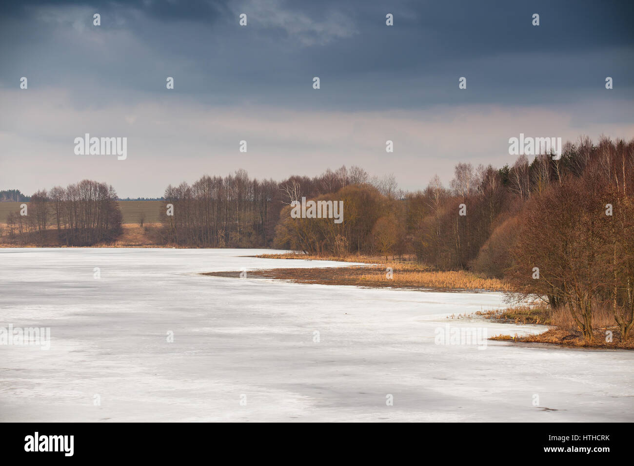 Early spring. Mud season. Lake under ice and snow melting. Cloudy ...