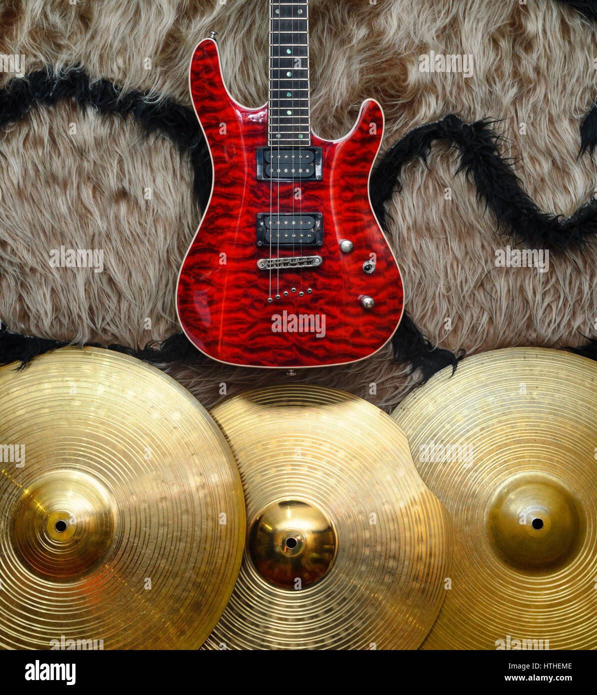 Red Electric guitar with three cymbals on faux fur wall. Musical ...