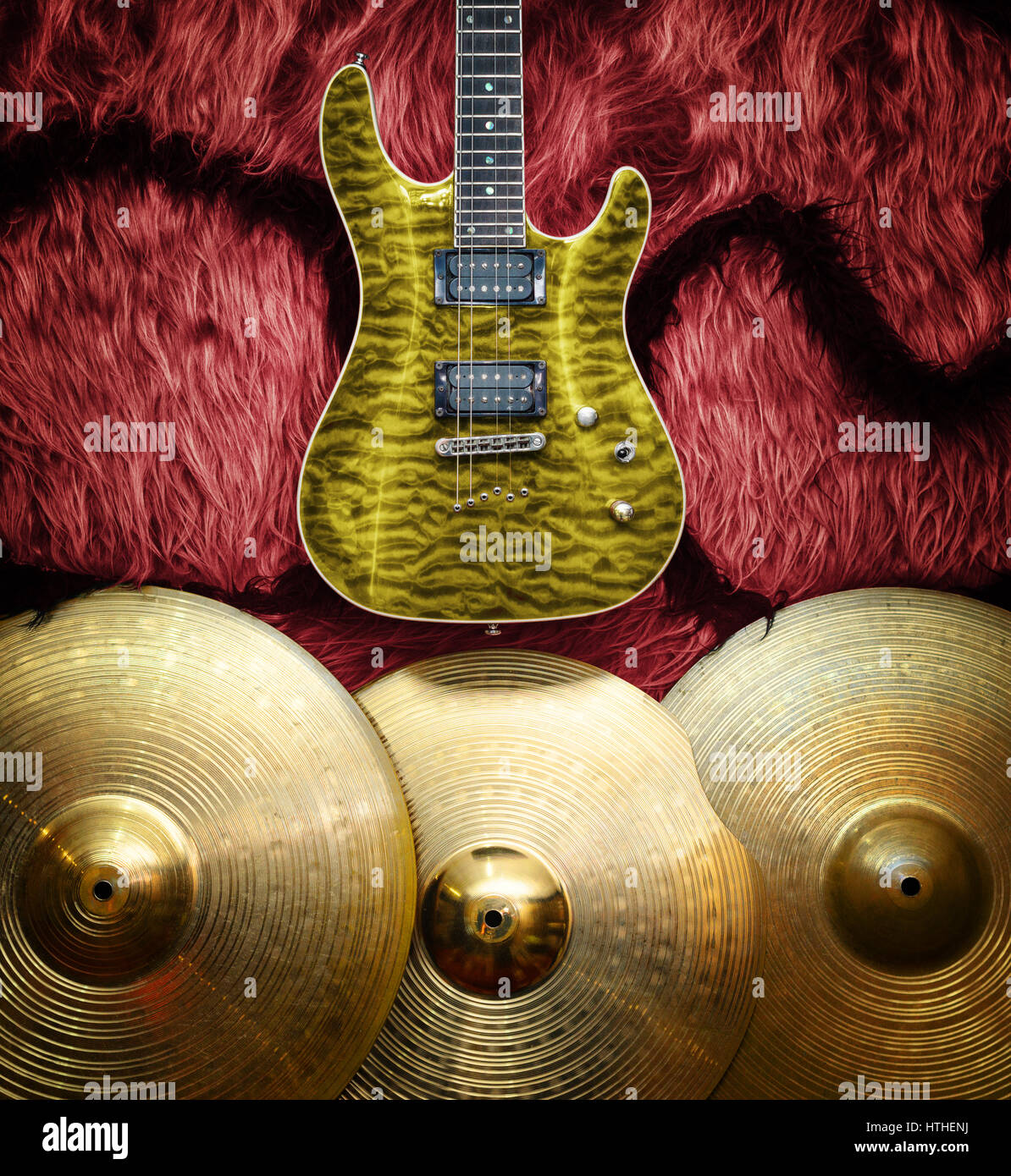 Yellow electric guitar with three cymbals on faux fur wall. Musical ...