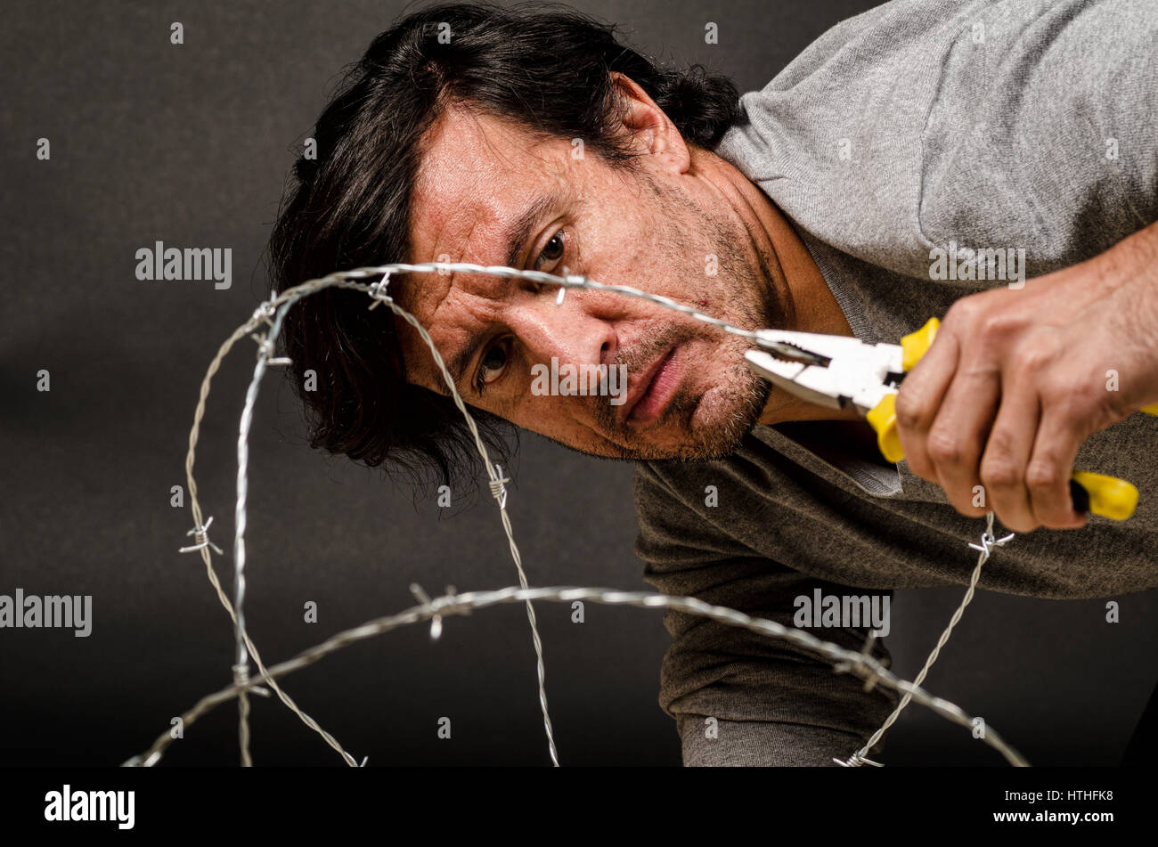 Latino male trying to break through a barbed fence, a conceptual shot ...