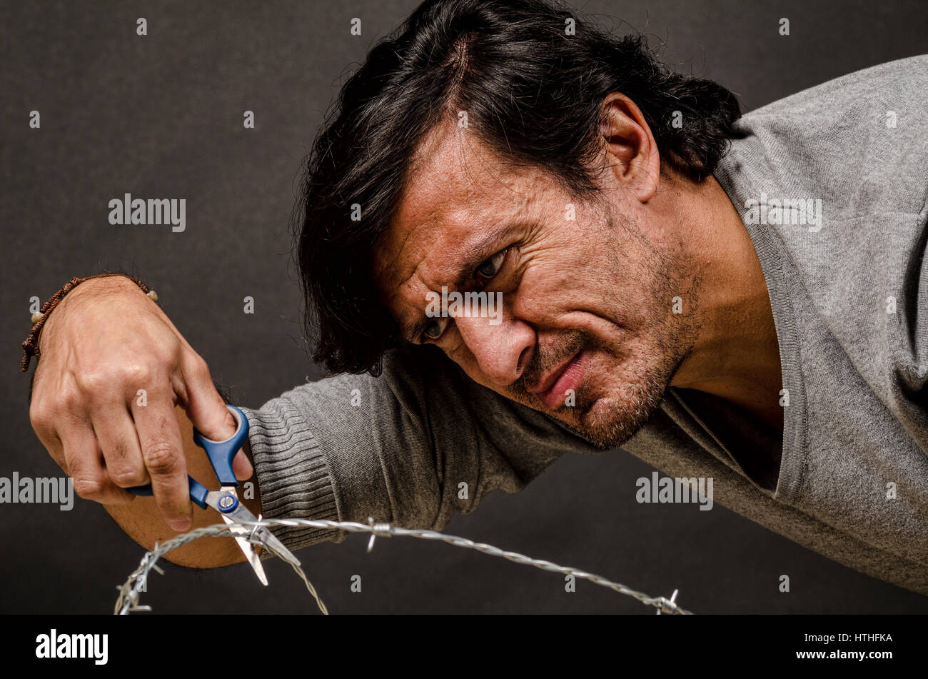 Latino male trying to break through a barbed fence, a conceptual shot ...