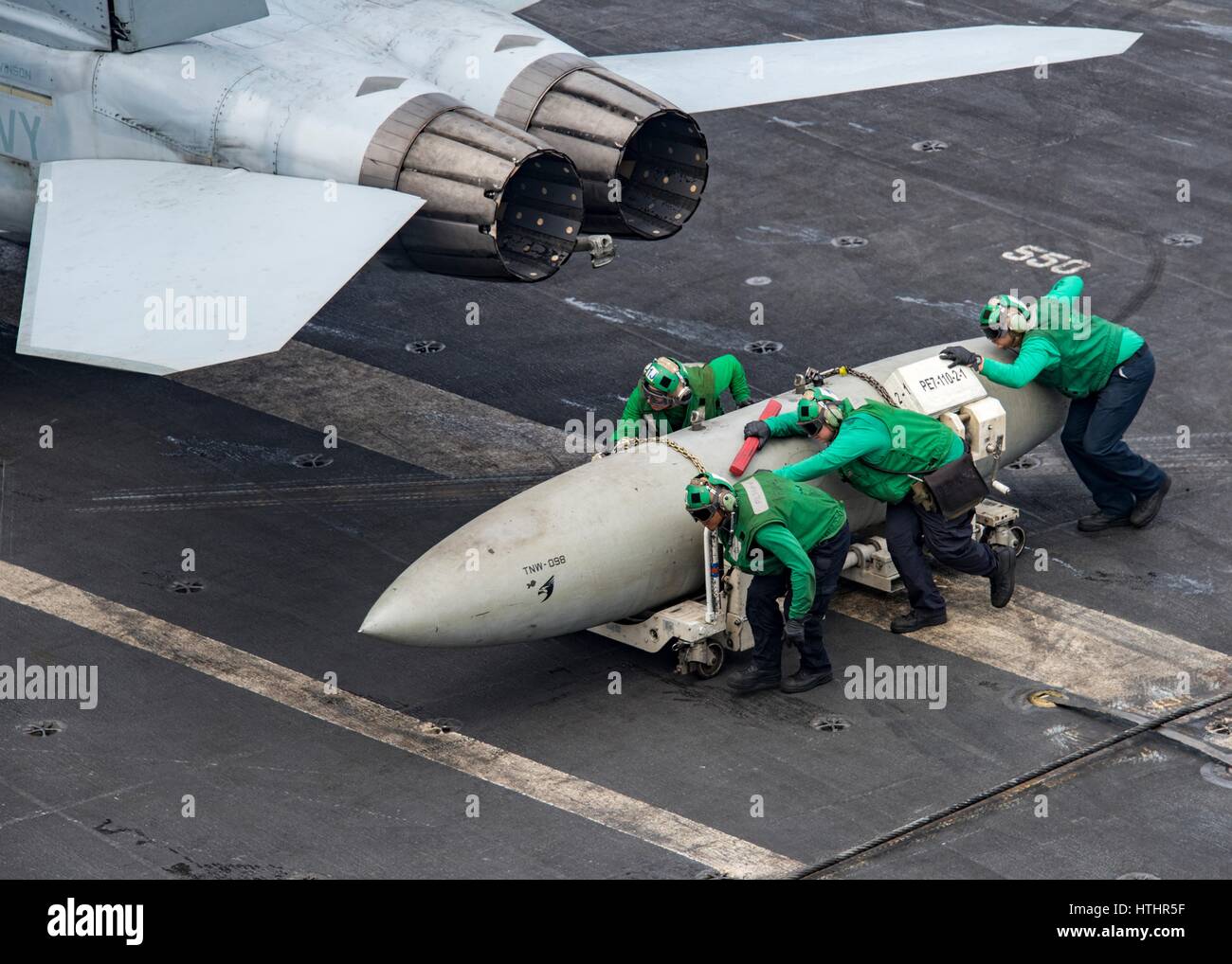 U.S. sailors move a fuel pod on the flight deck aboard the USN Nimitz ...