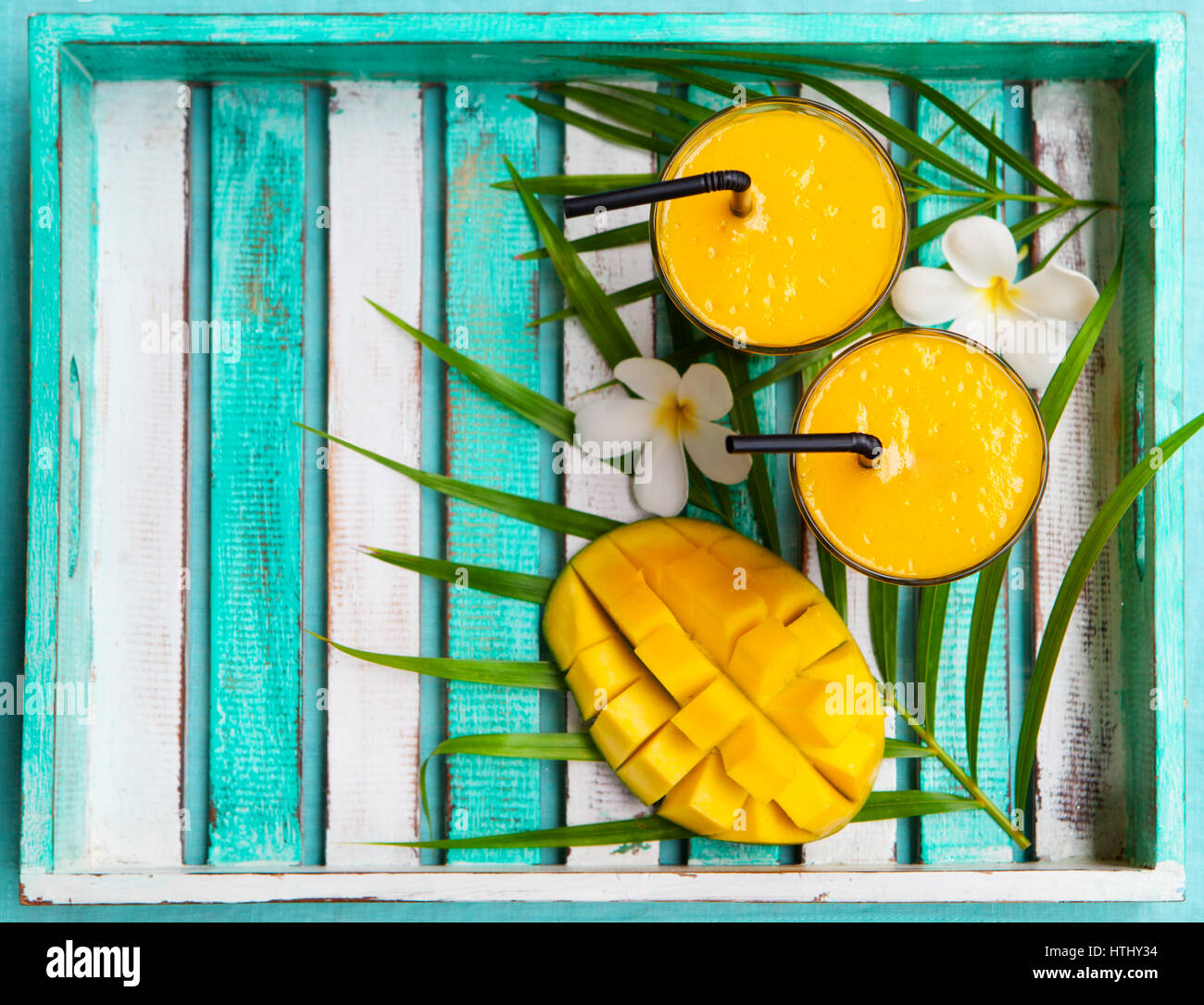 Mango smoothie, juice and fresh mango on a outdoor tropical background ...