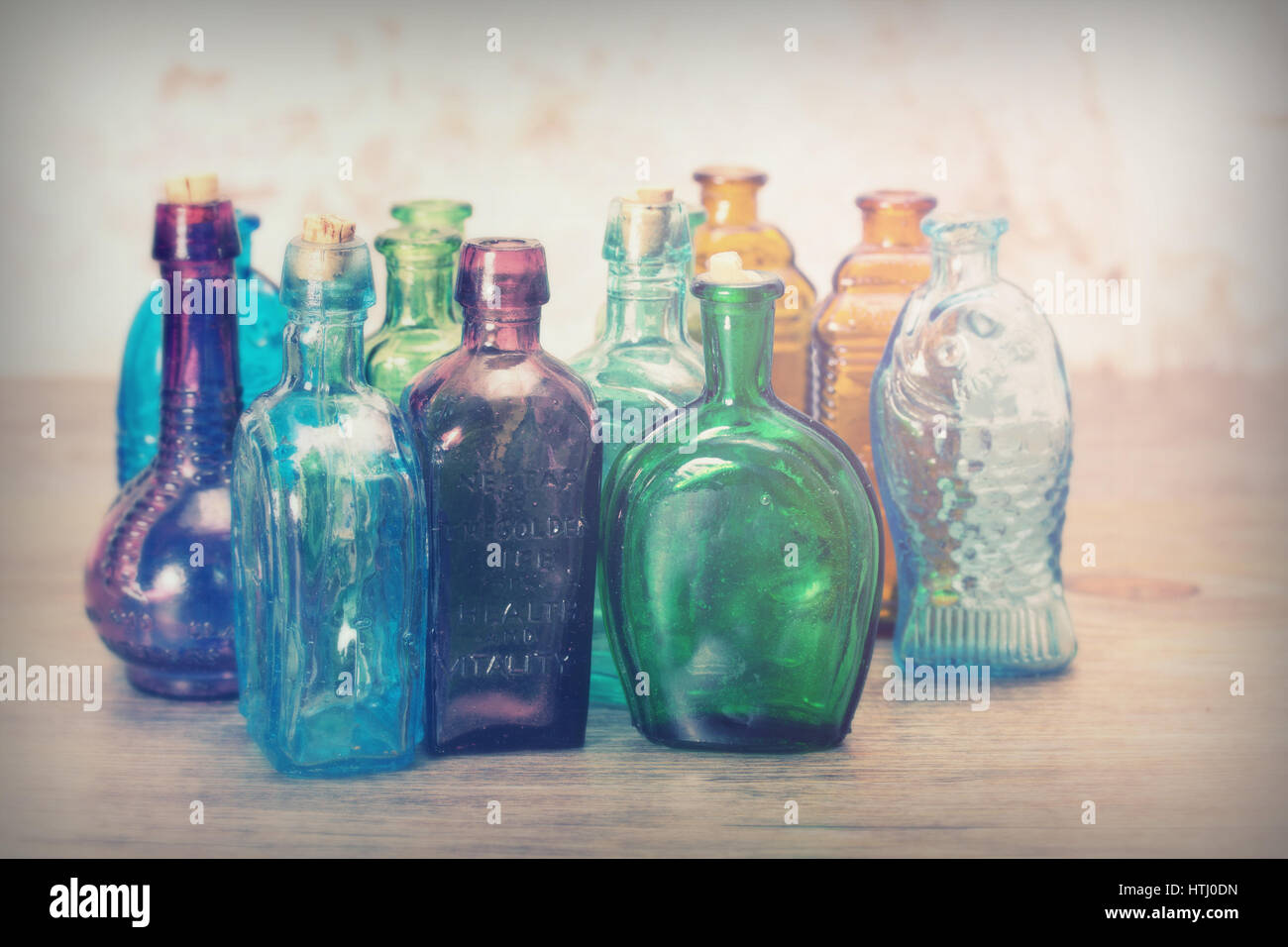 Selection of coloured glass bottles on a rustic background Stock Photo ...