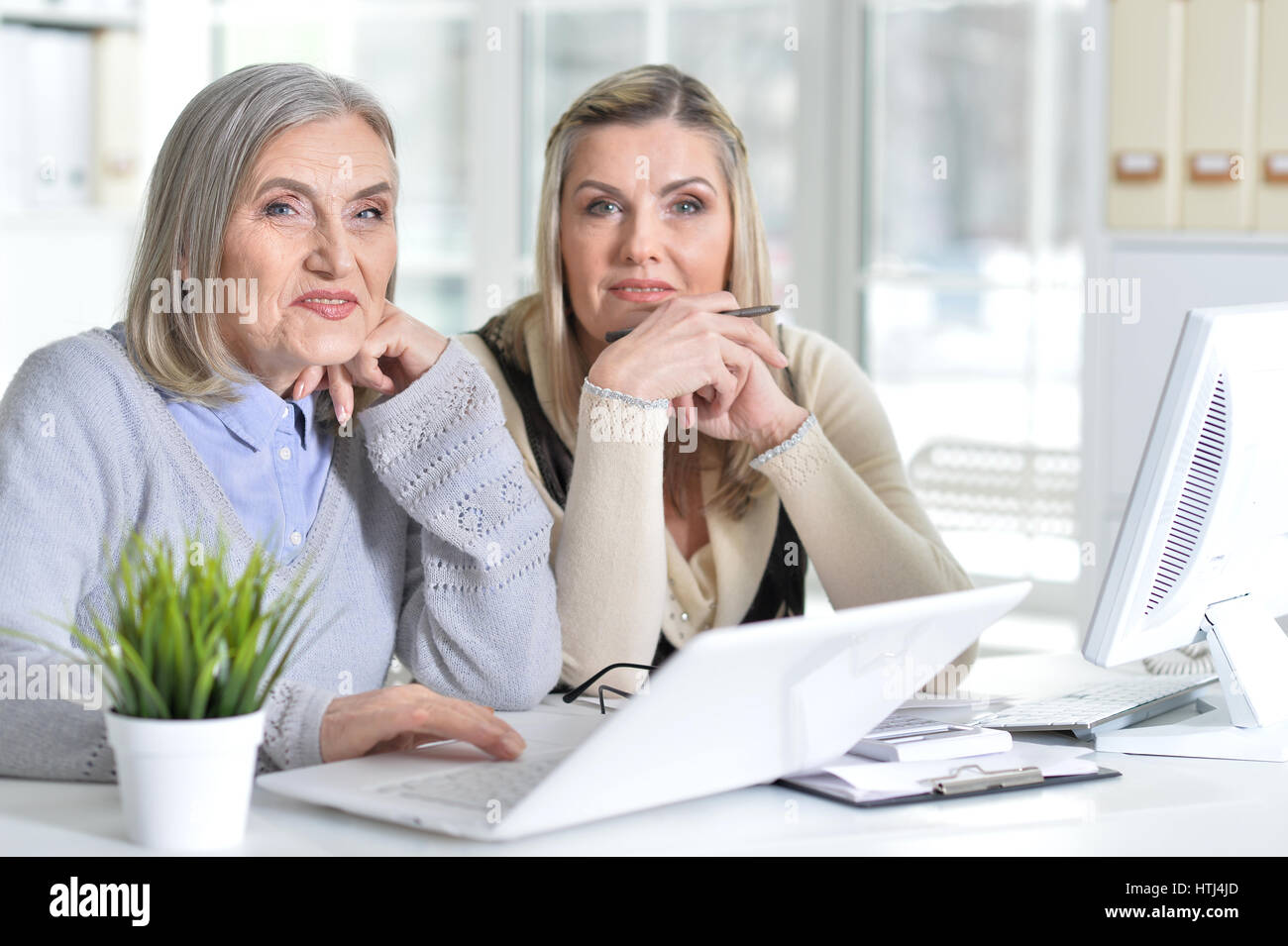 two mature women using laptop and smiling at camera Stock Photo - Alamy