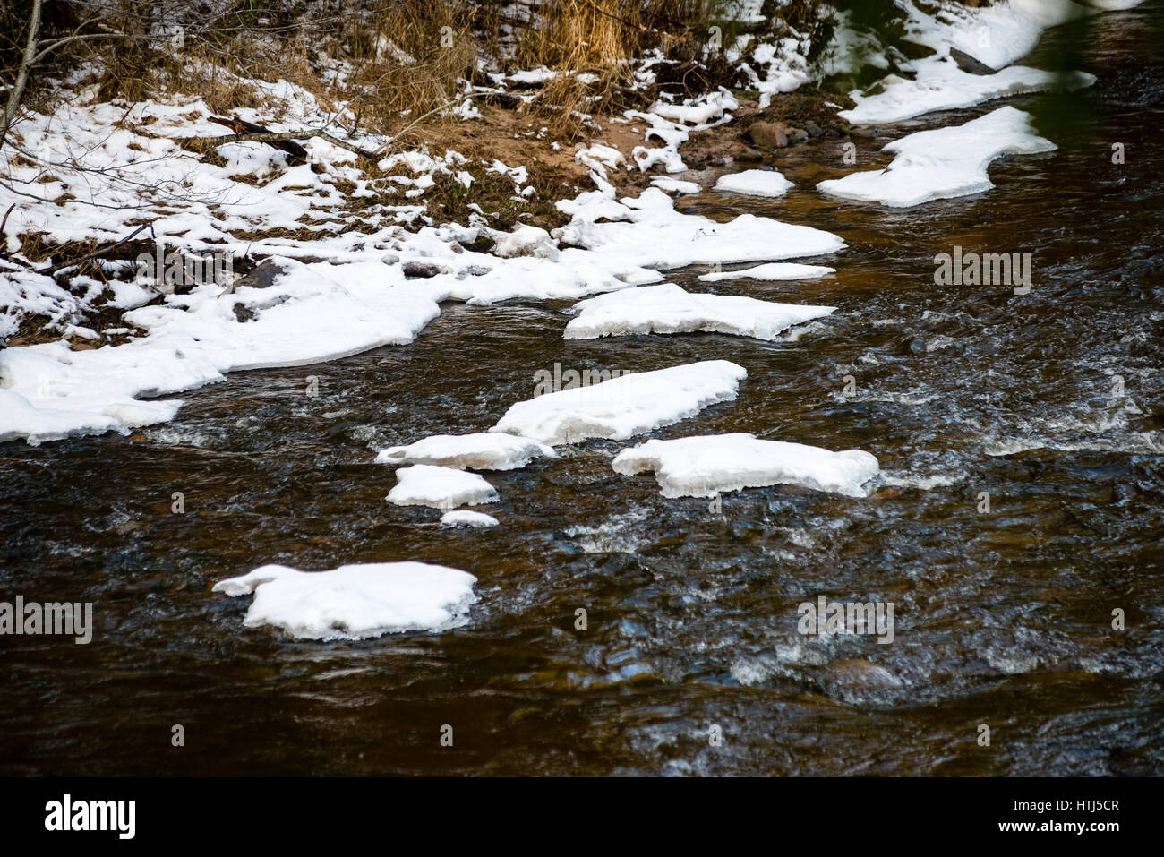 frozen countryside scene in winter with snow. iced river with blocks of ...