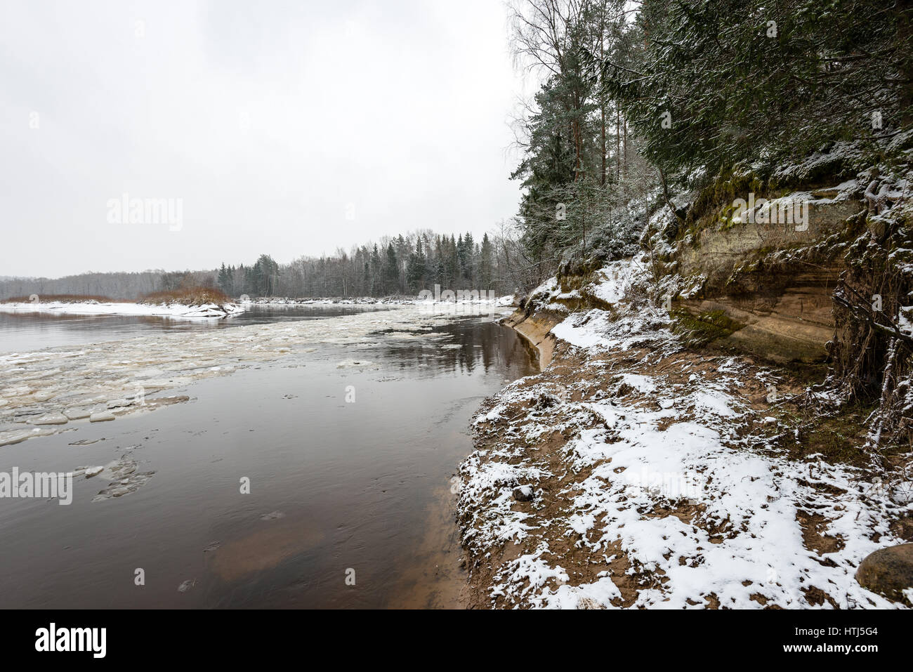 frozen countryside scene in winter with snow. iced river with blocks of ...