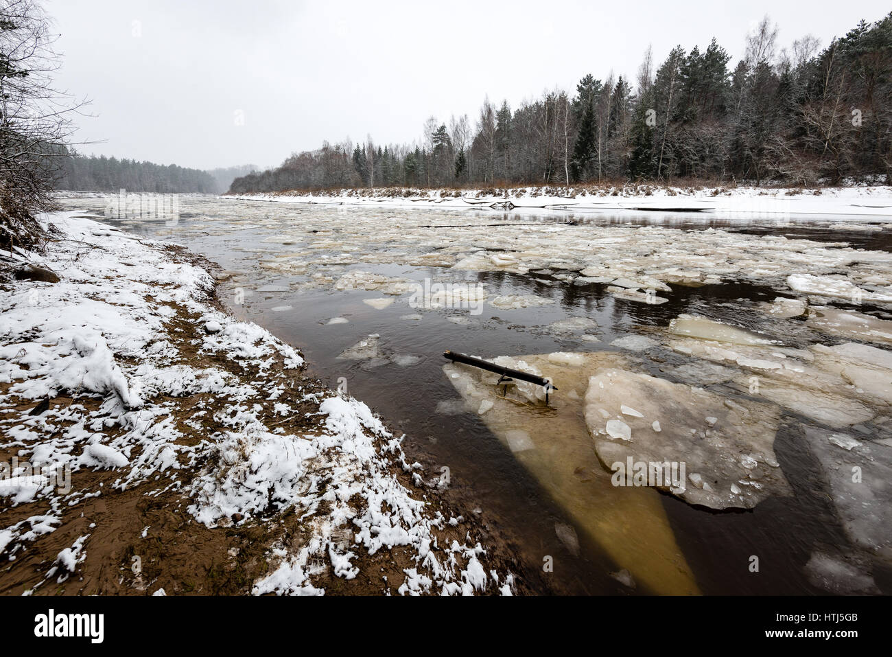 frozen countryside scene in winter with snow. iced river with blocks of ...