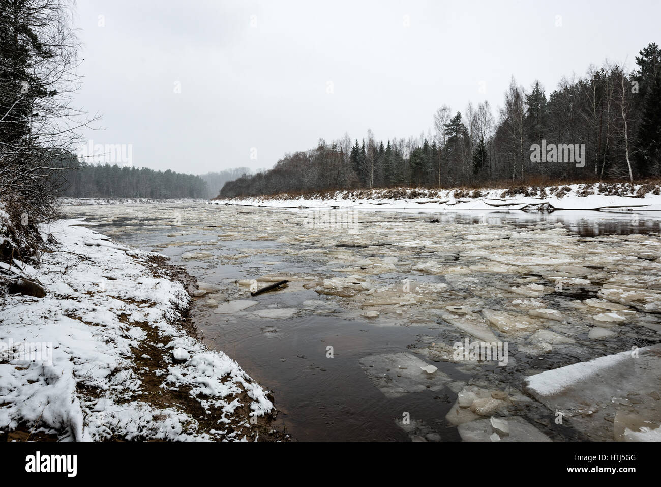 frozen countryside scene in winter with snow. iced river with blocks of ...