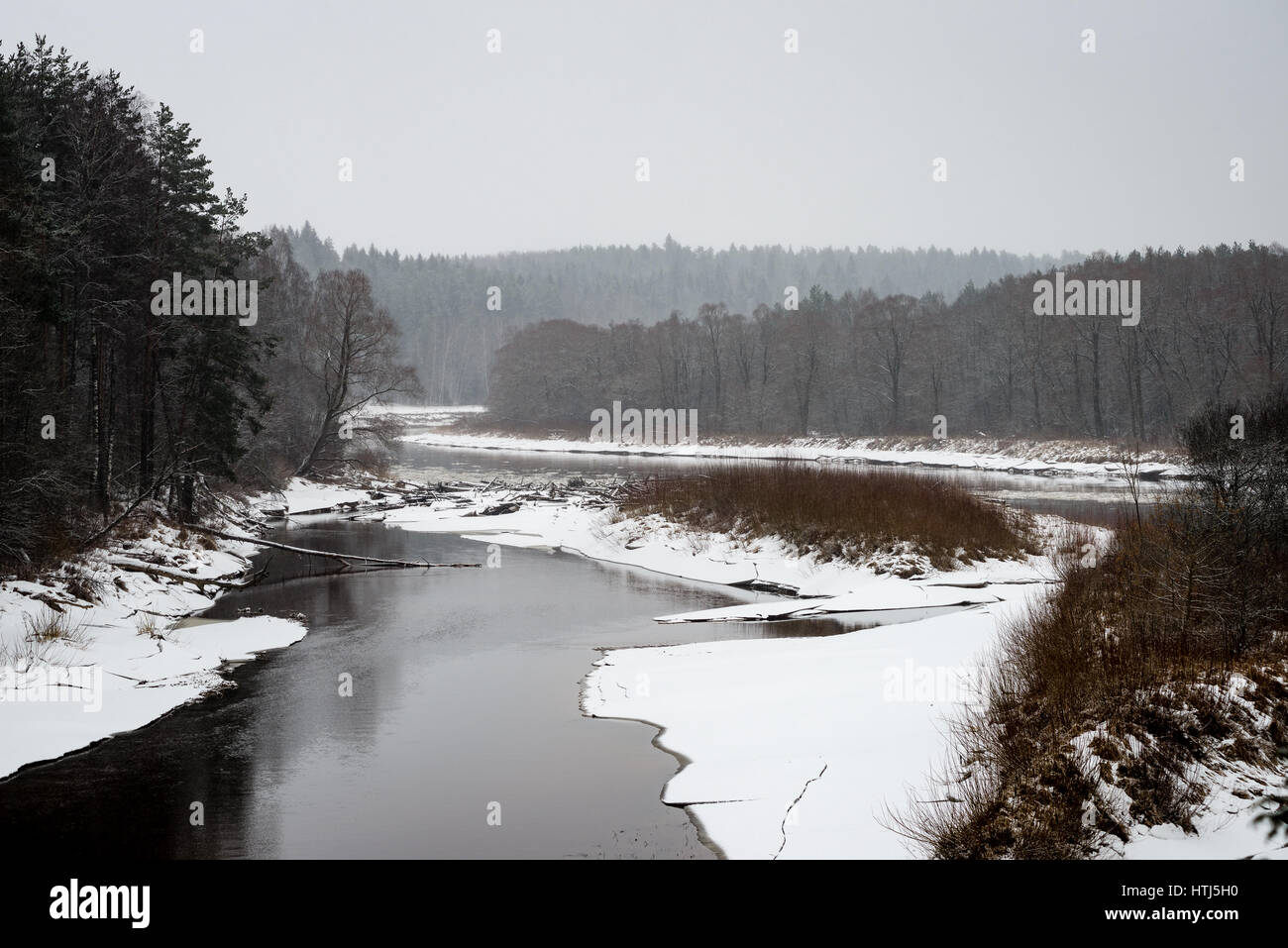 frozen countryside scene in winter with snow. iced river with blocks of ...