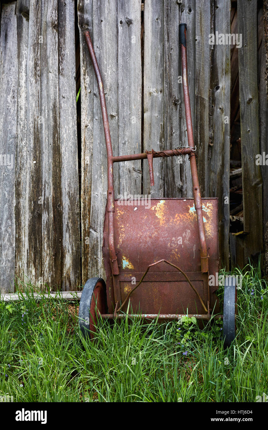 An old and rusty wheelbarrow on wooden background Stock Photo - Alamy