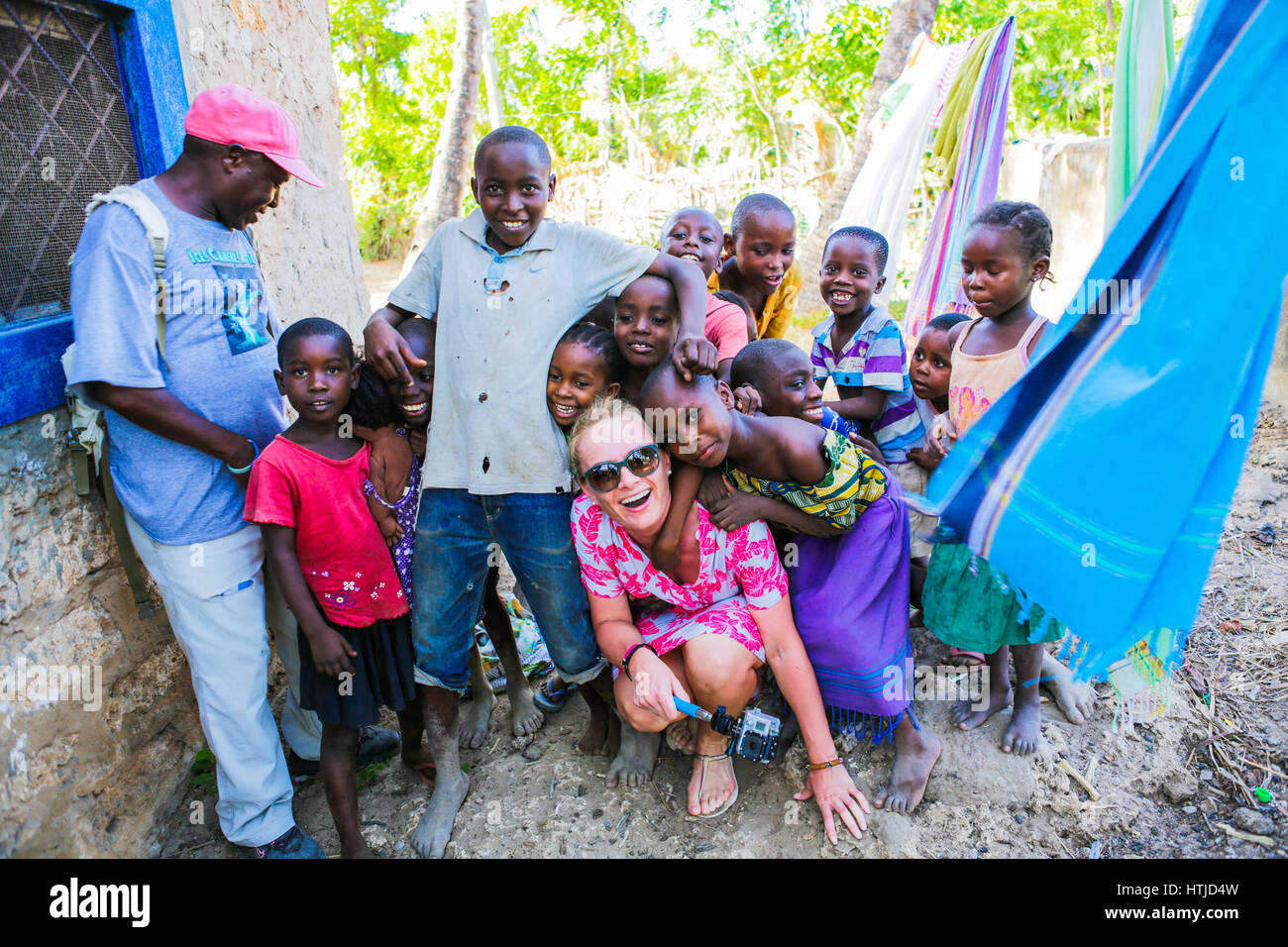 Female tourist exploring local village. Posing with local children ...