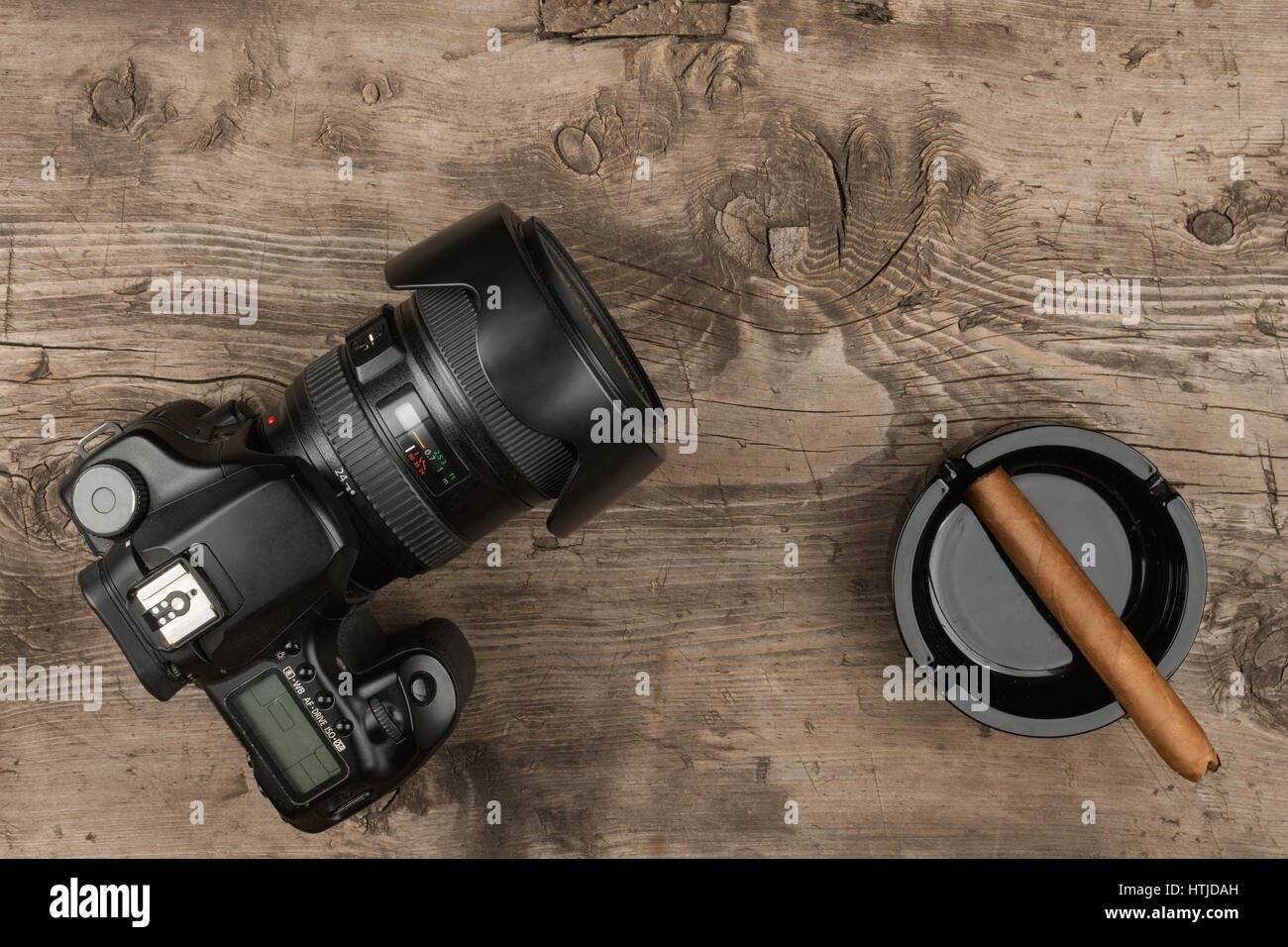 Digital camera and ashtray with a cigar on an old wood. View from above ...