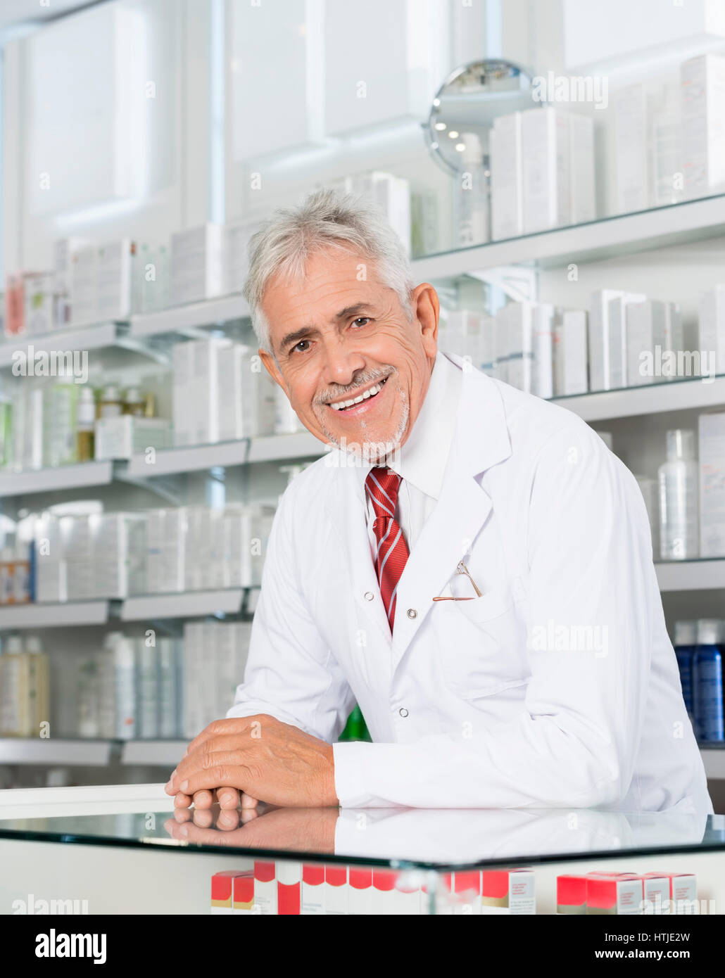 Confident Pharmacist Smiling While Leaning On Counter Stock Photo - Alamy