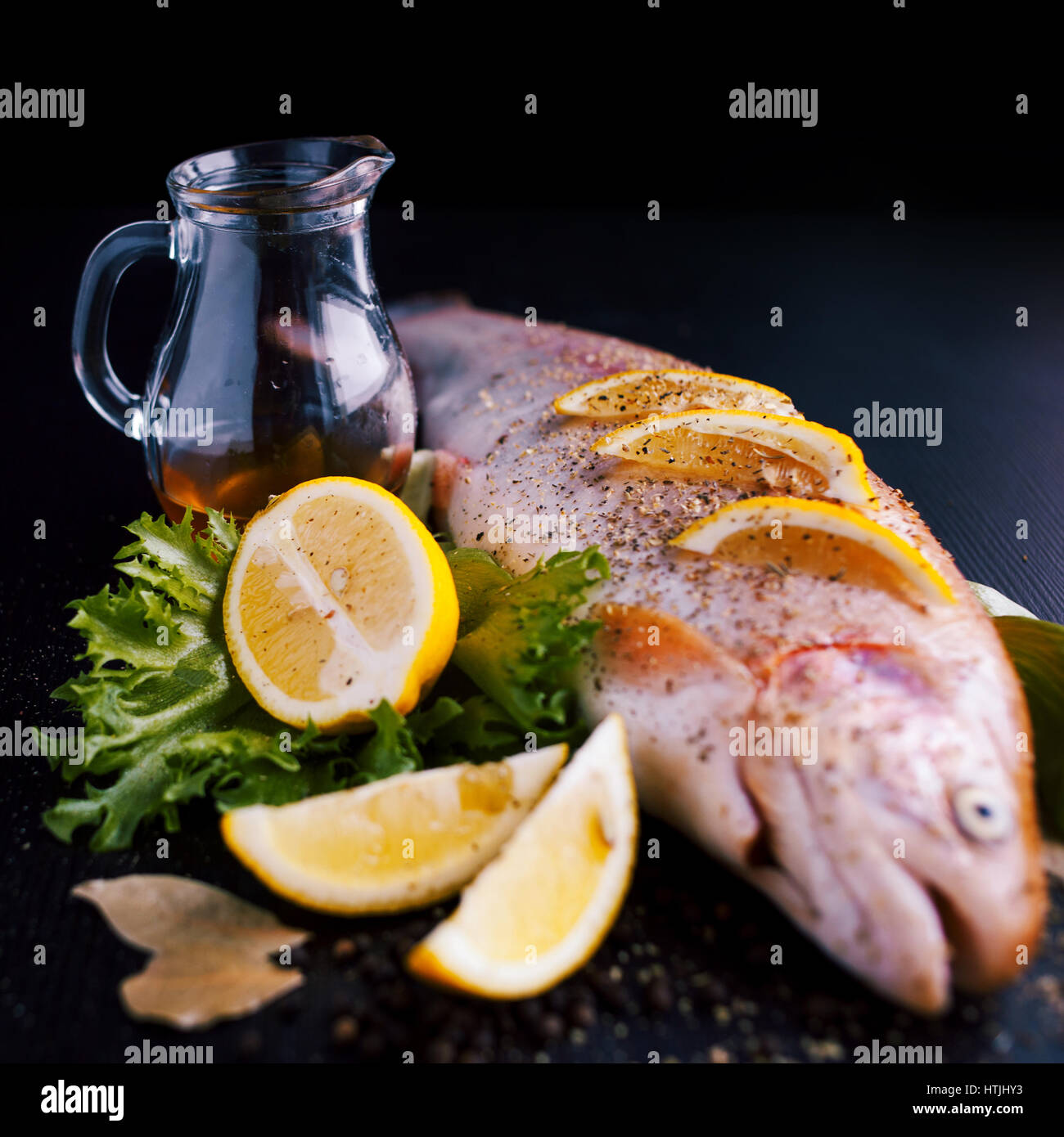 Fresh trout and ingredients to prepare fish dishes on black table ...